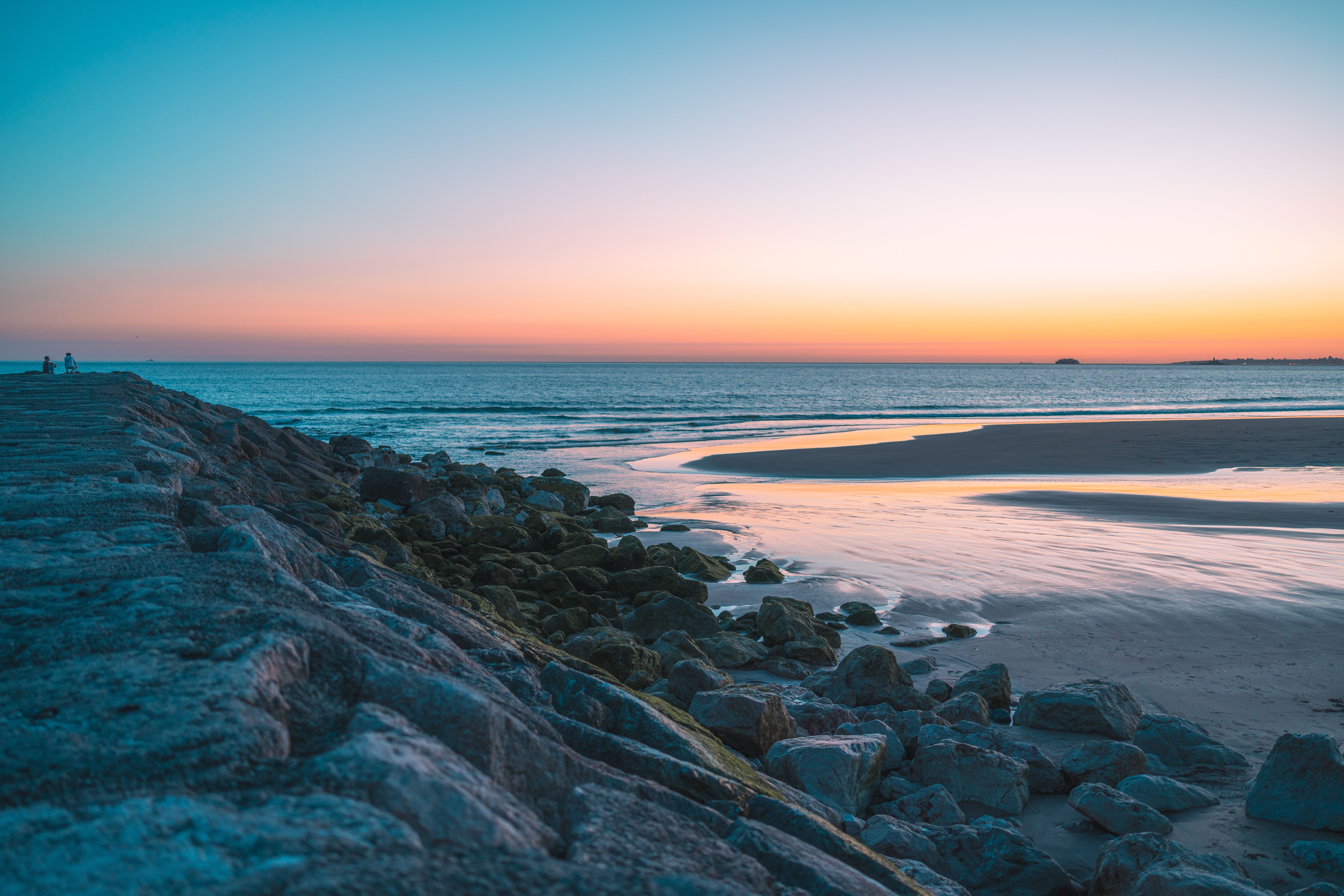 Tourists on a Rocky Breakwater Watching the Sunset over the Ocean ...