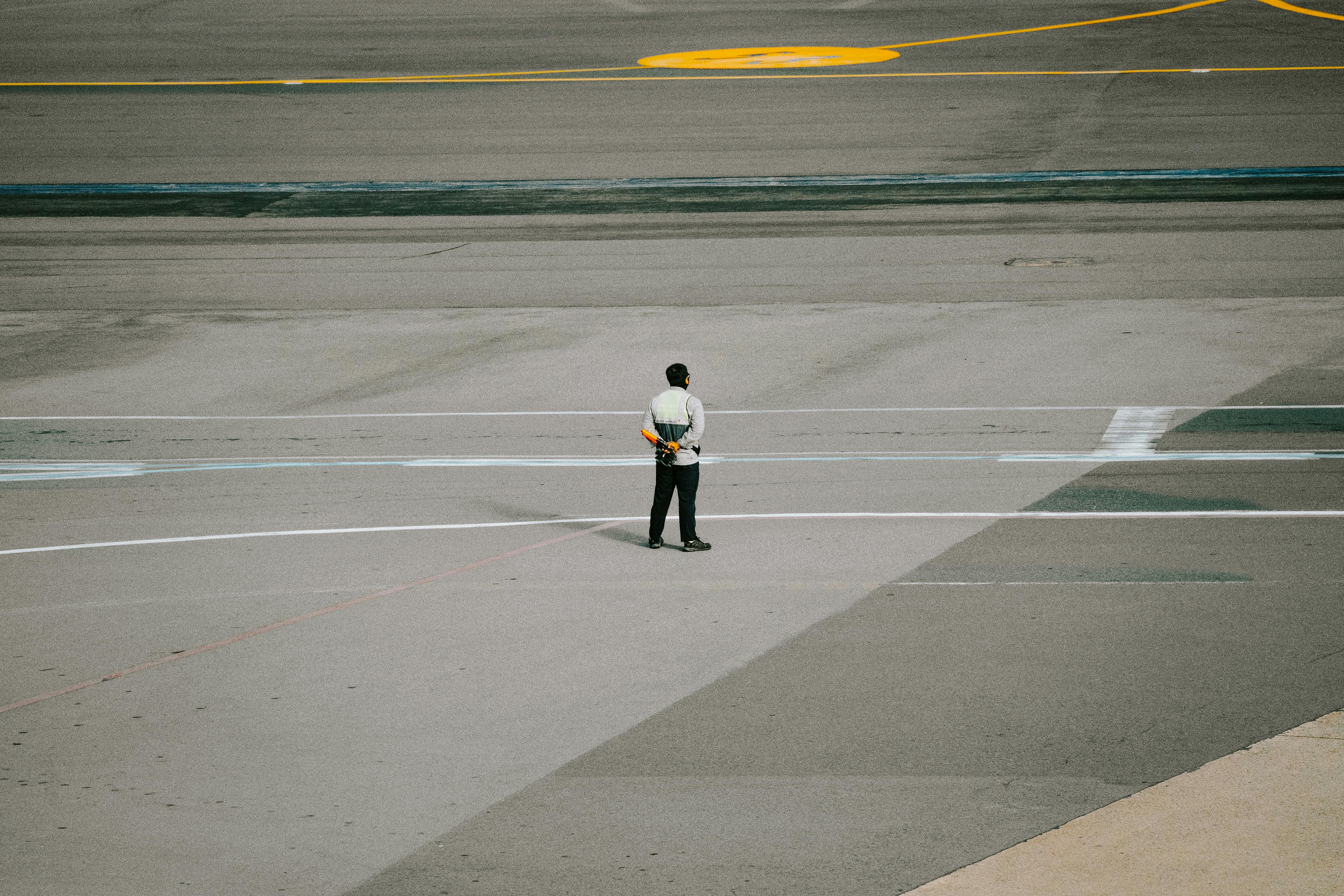 Person Standing and Working at Airport Runway · Free Stock Photo