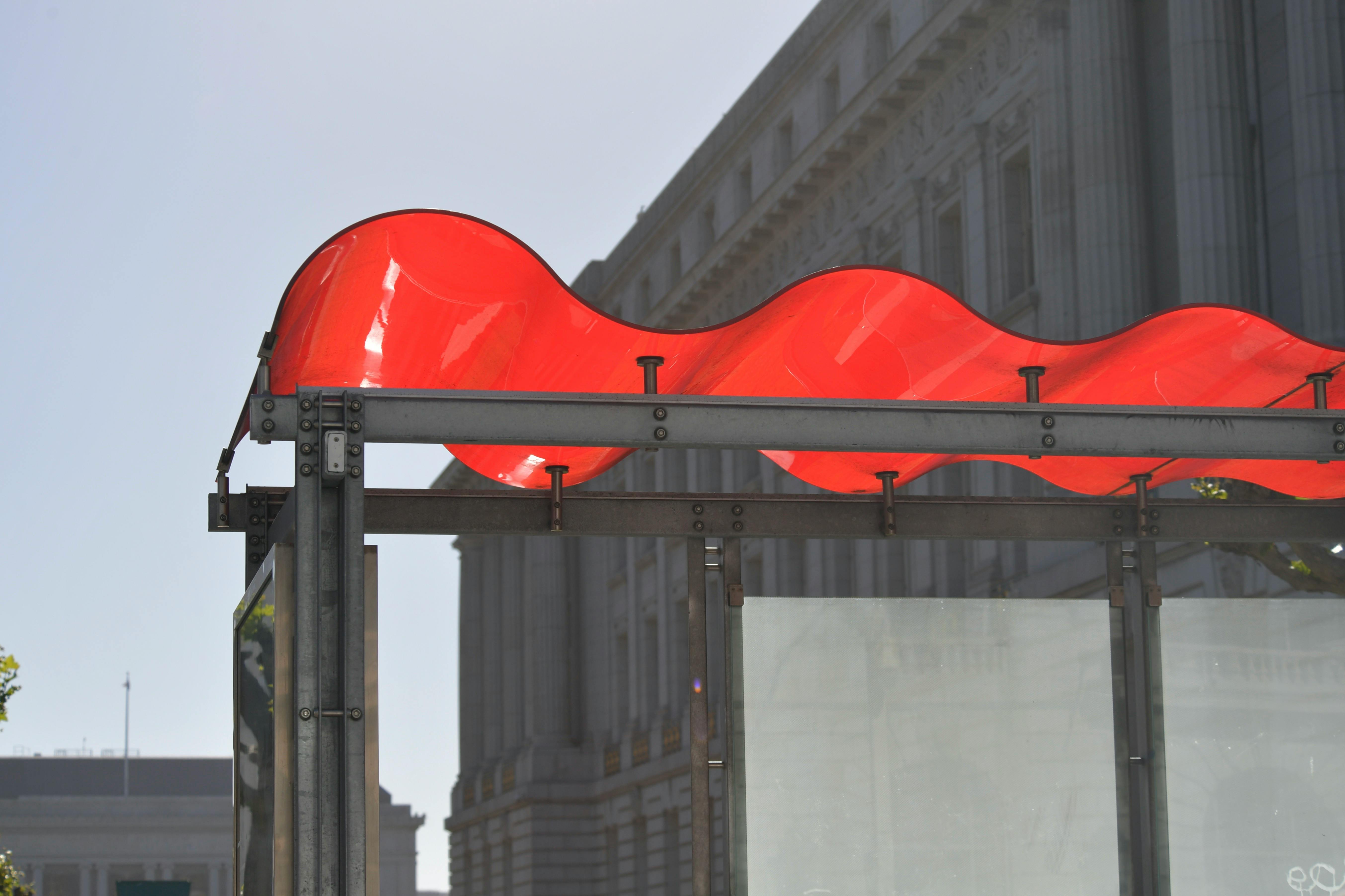 A red bus stop with a red roof and a white building · Free Stock Photo