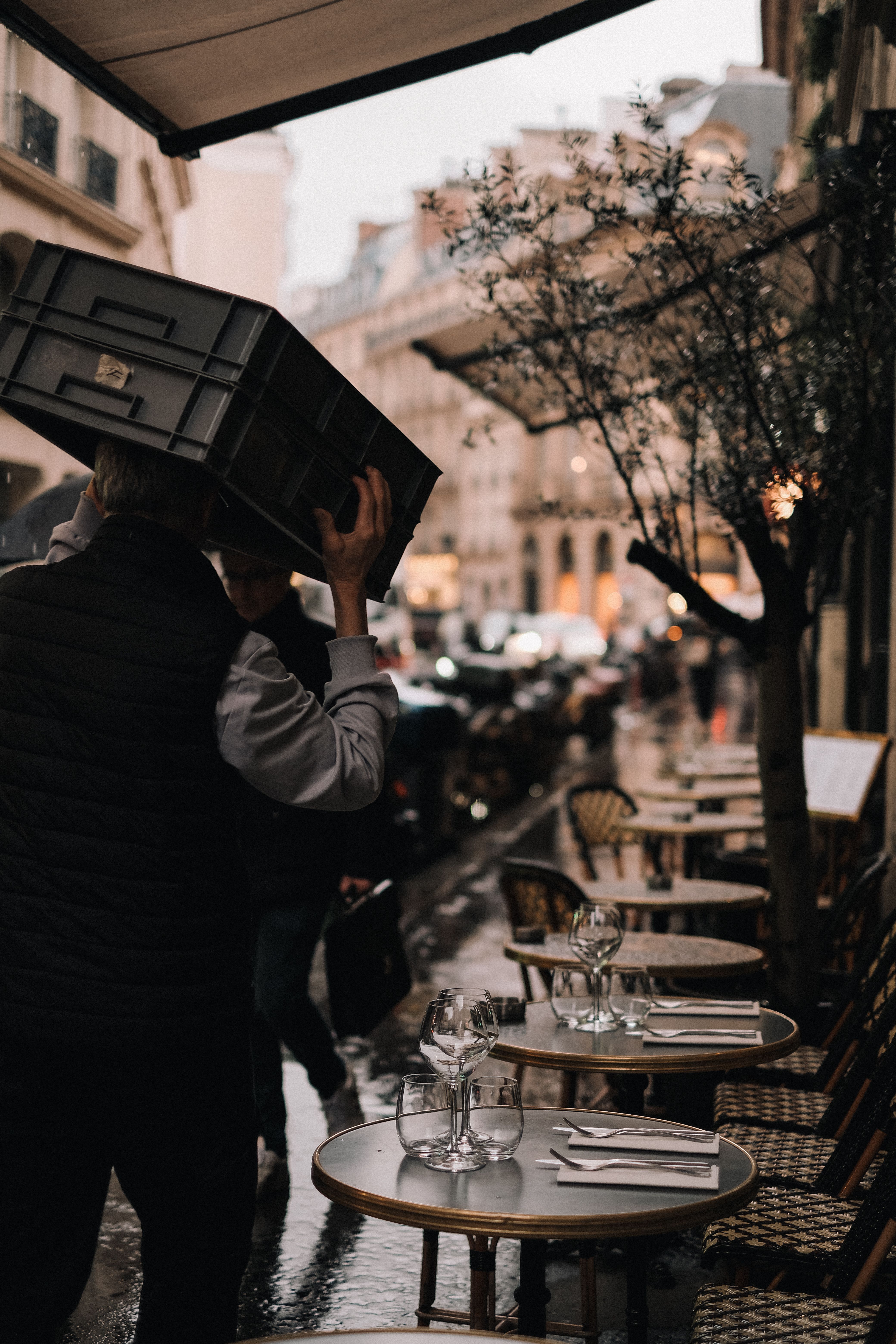 Back View of a Man Carrying a Plastic Container next to Set Tables on a ...