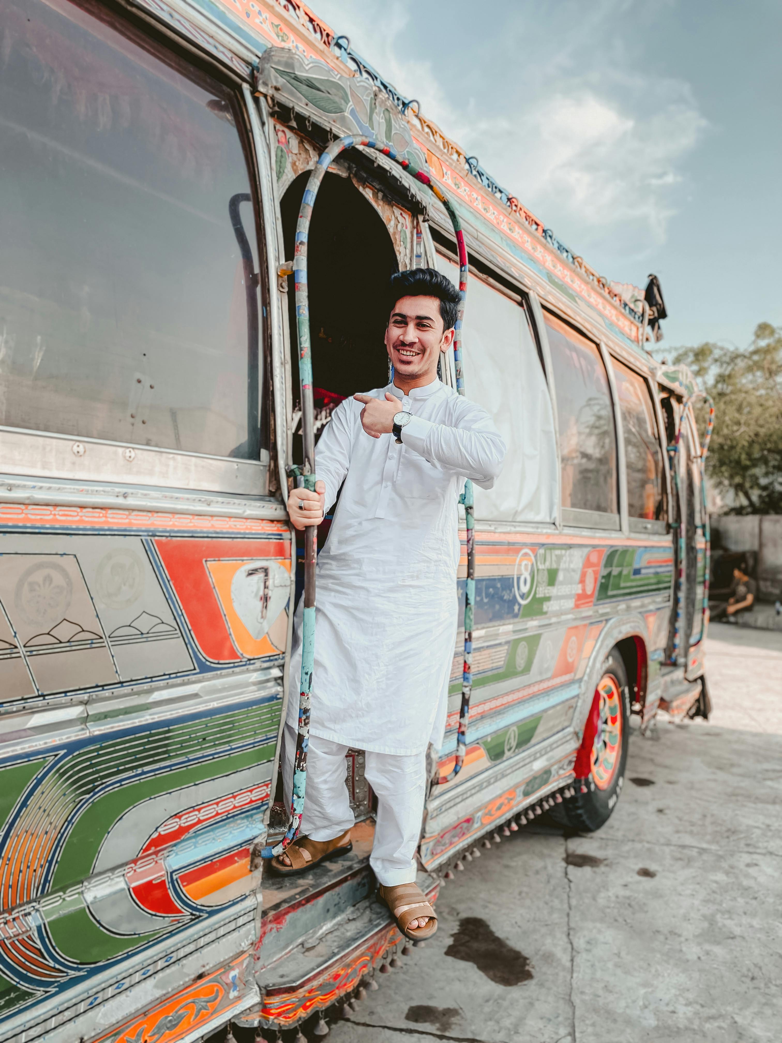 Smiling Man in Traditional Clothing on Bus Stairs · Free Stock Photo