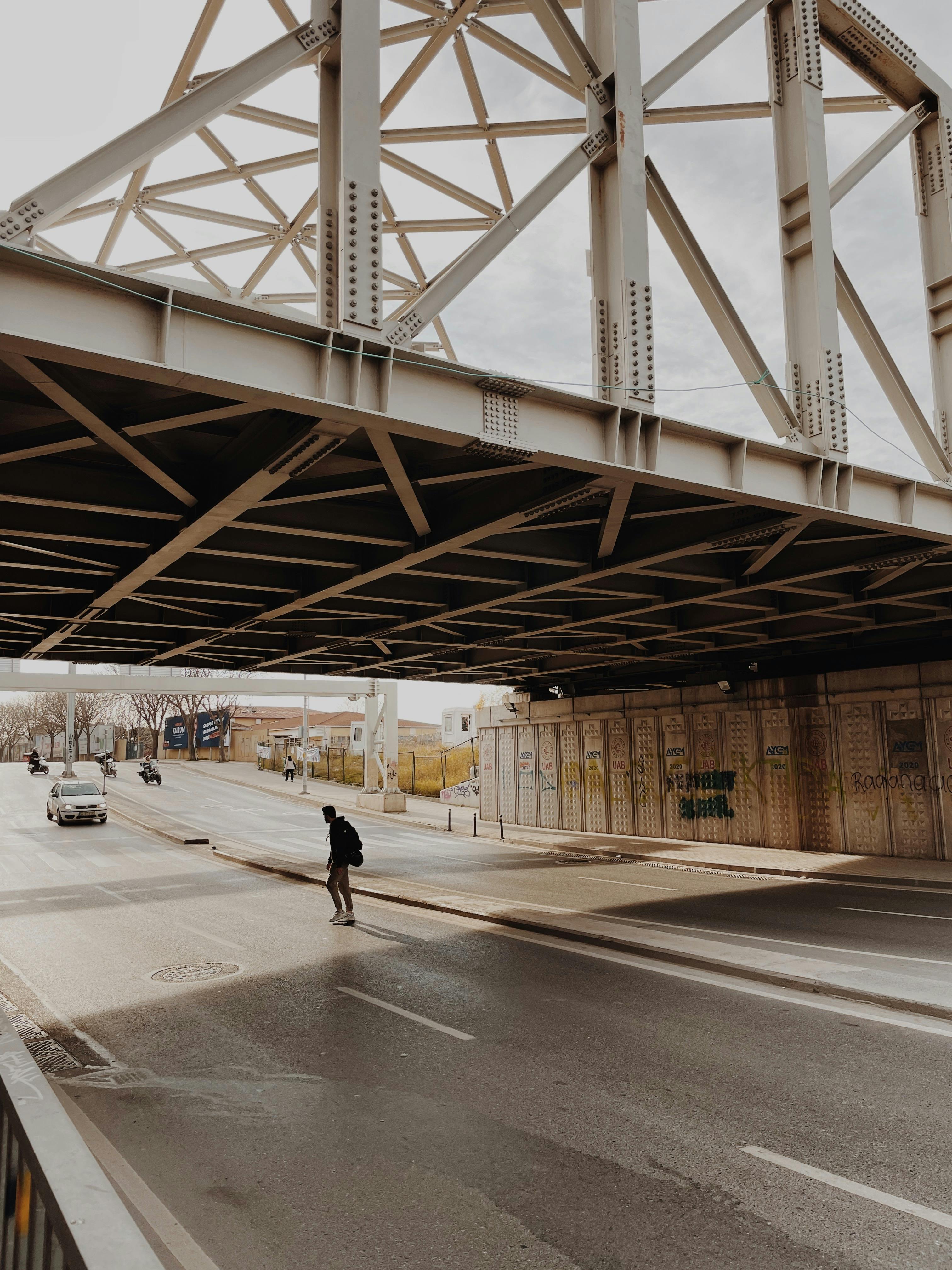 Person Walking on Street with Car under Bridge · Free Stock Photo