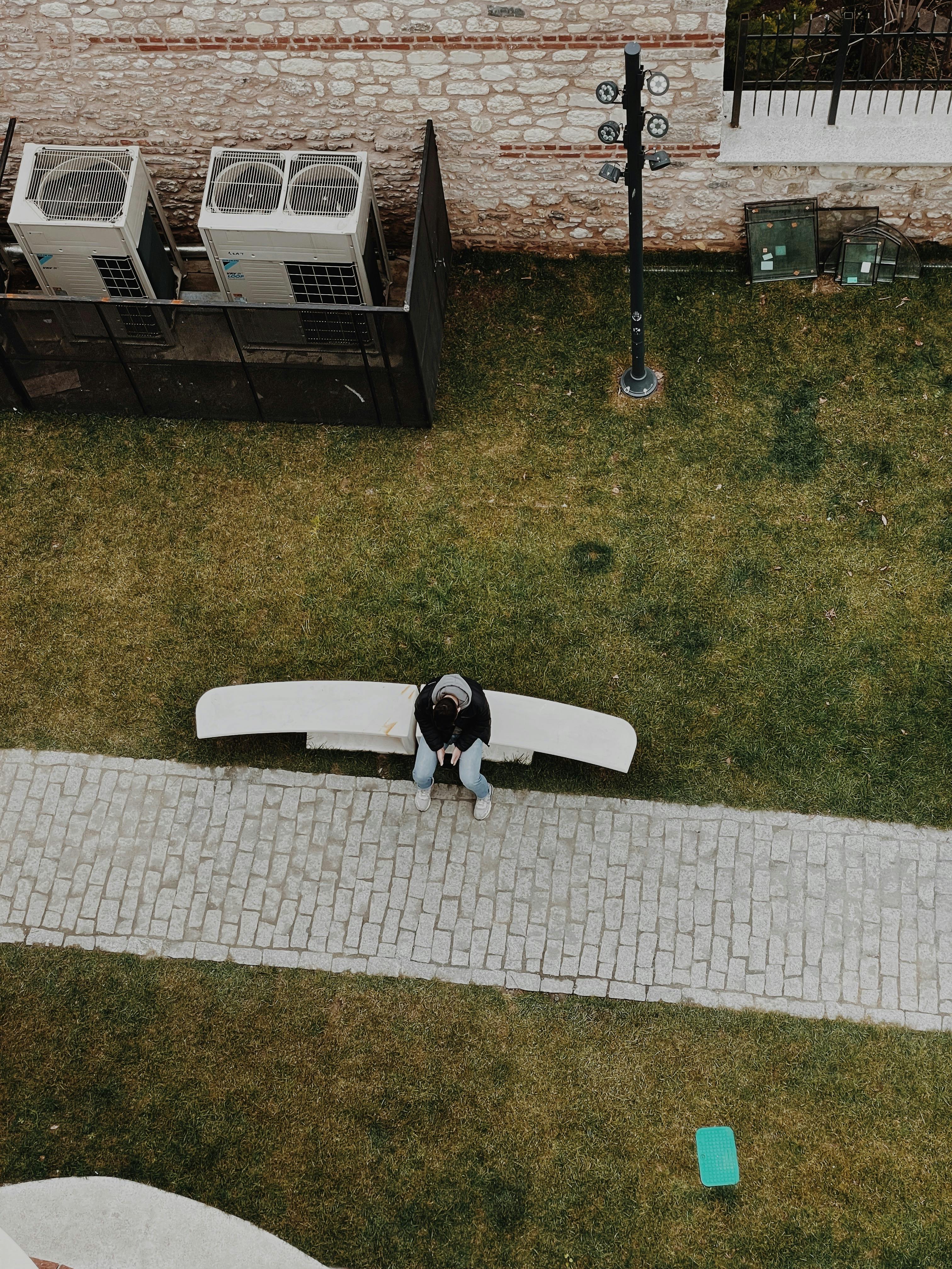 Top View of Person Sitting on White Curved Bench between Buildings ...