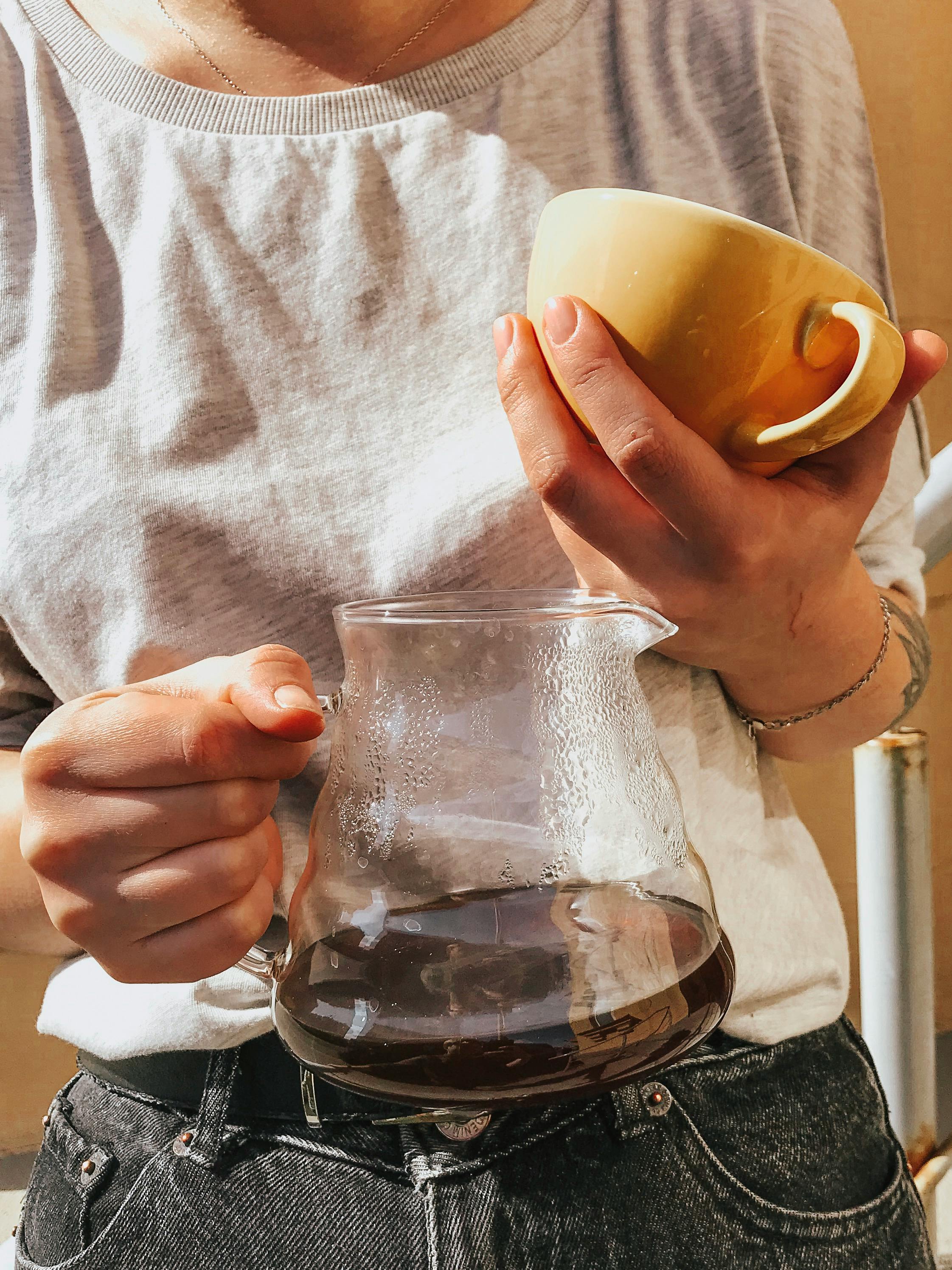 Close-up Photo of Woman Holding Glass Pitcher of Coffee and a Ceramic ...