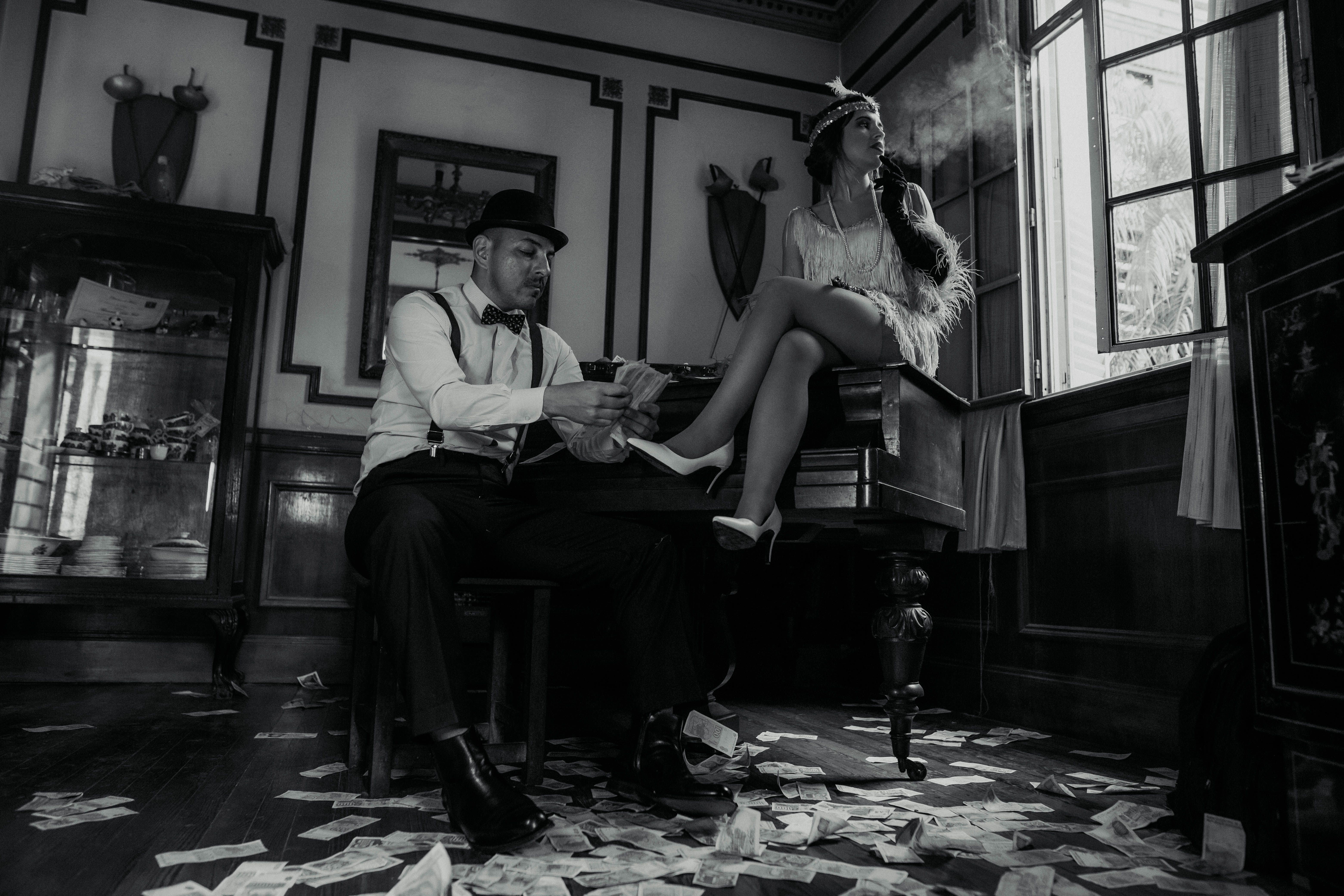 A Man Counting Money and a Woman Sitting on a Piano and Smoking a ...