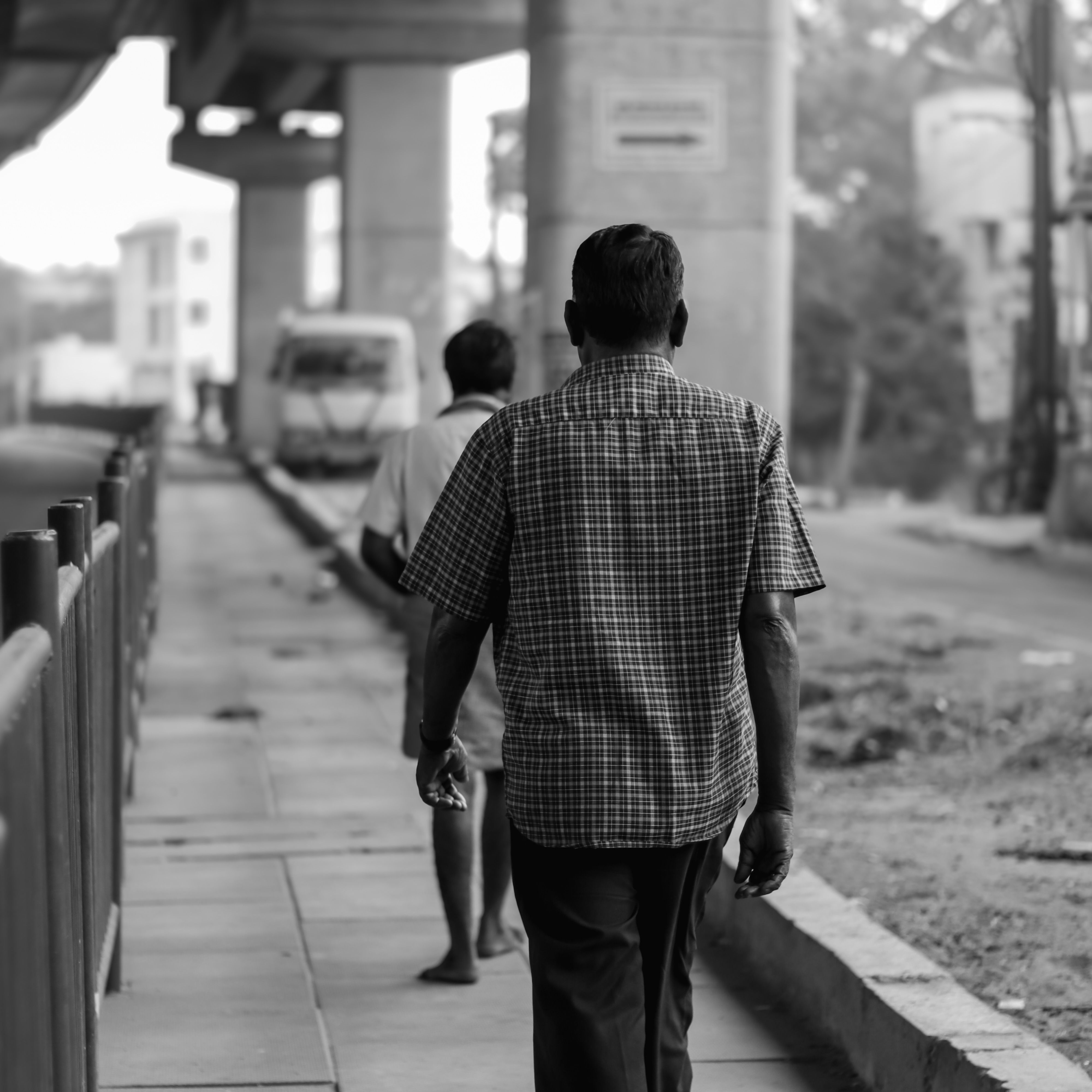 Back View of Man Walking on Sidewalk · Free Stock Photo