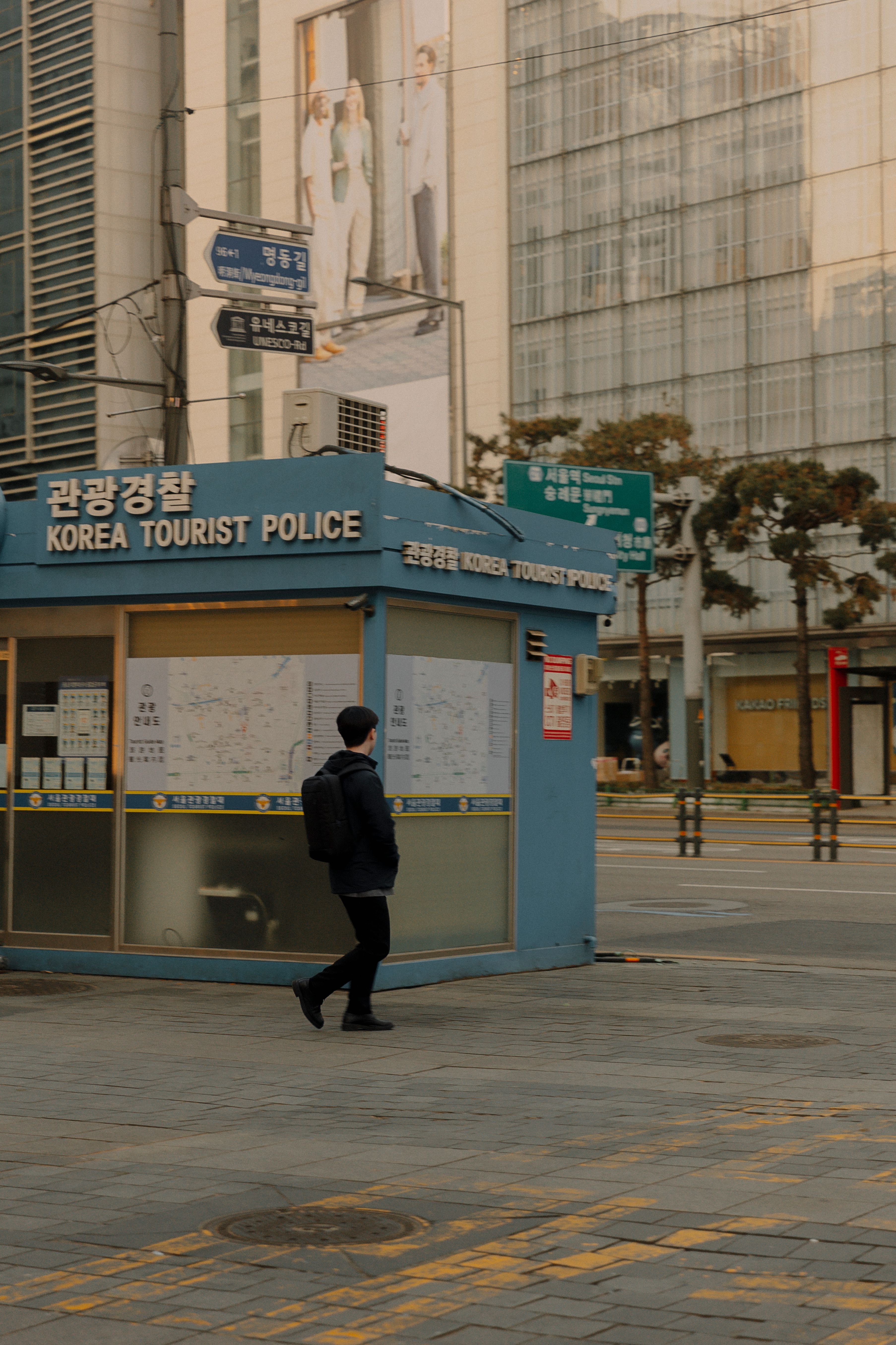 Young Man Walking by a Tourist Booth in Seoul · Free Stock Photo