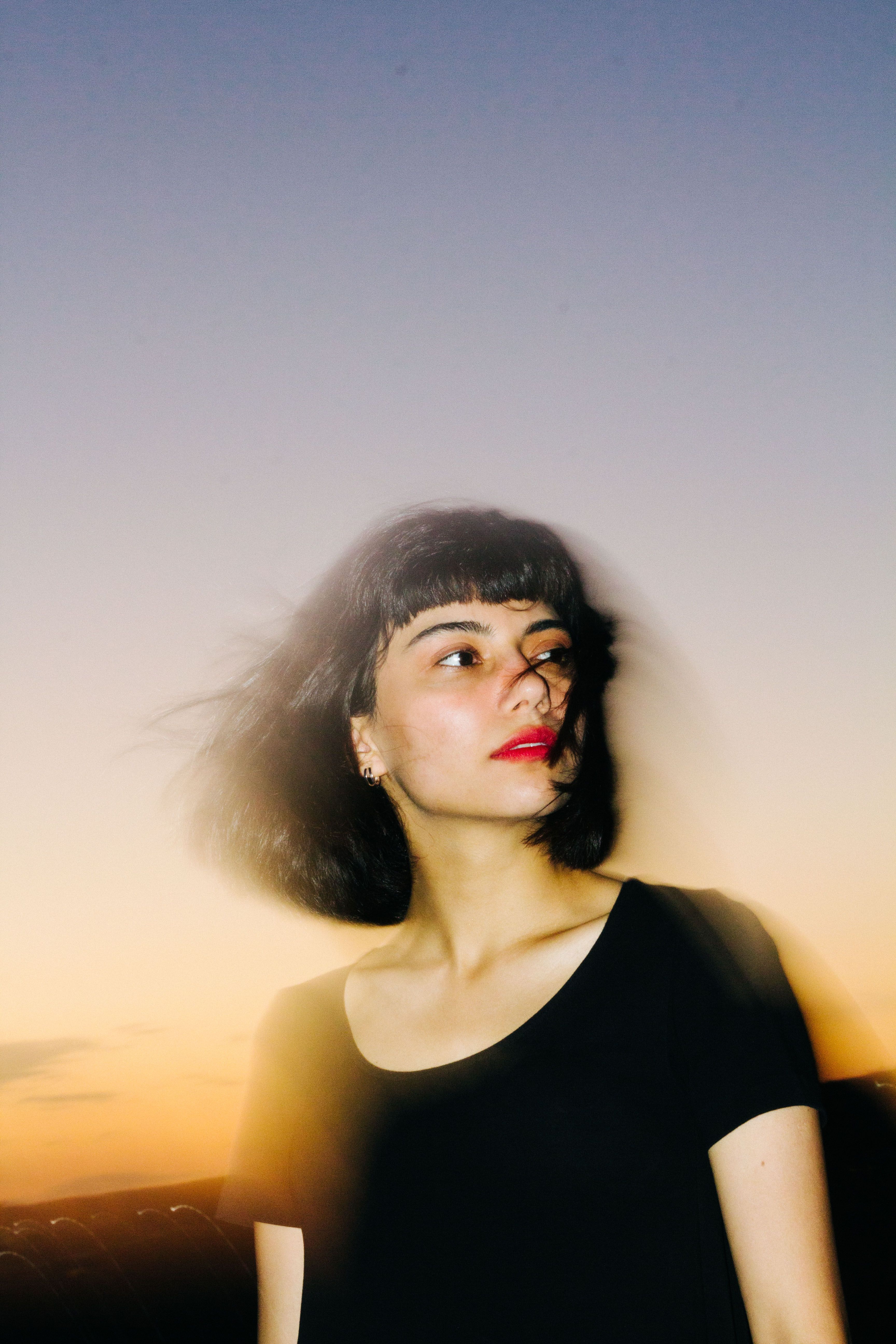 Blurry Photo of a Young Woman Standing Outside at Sunset · Free Stock Photo