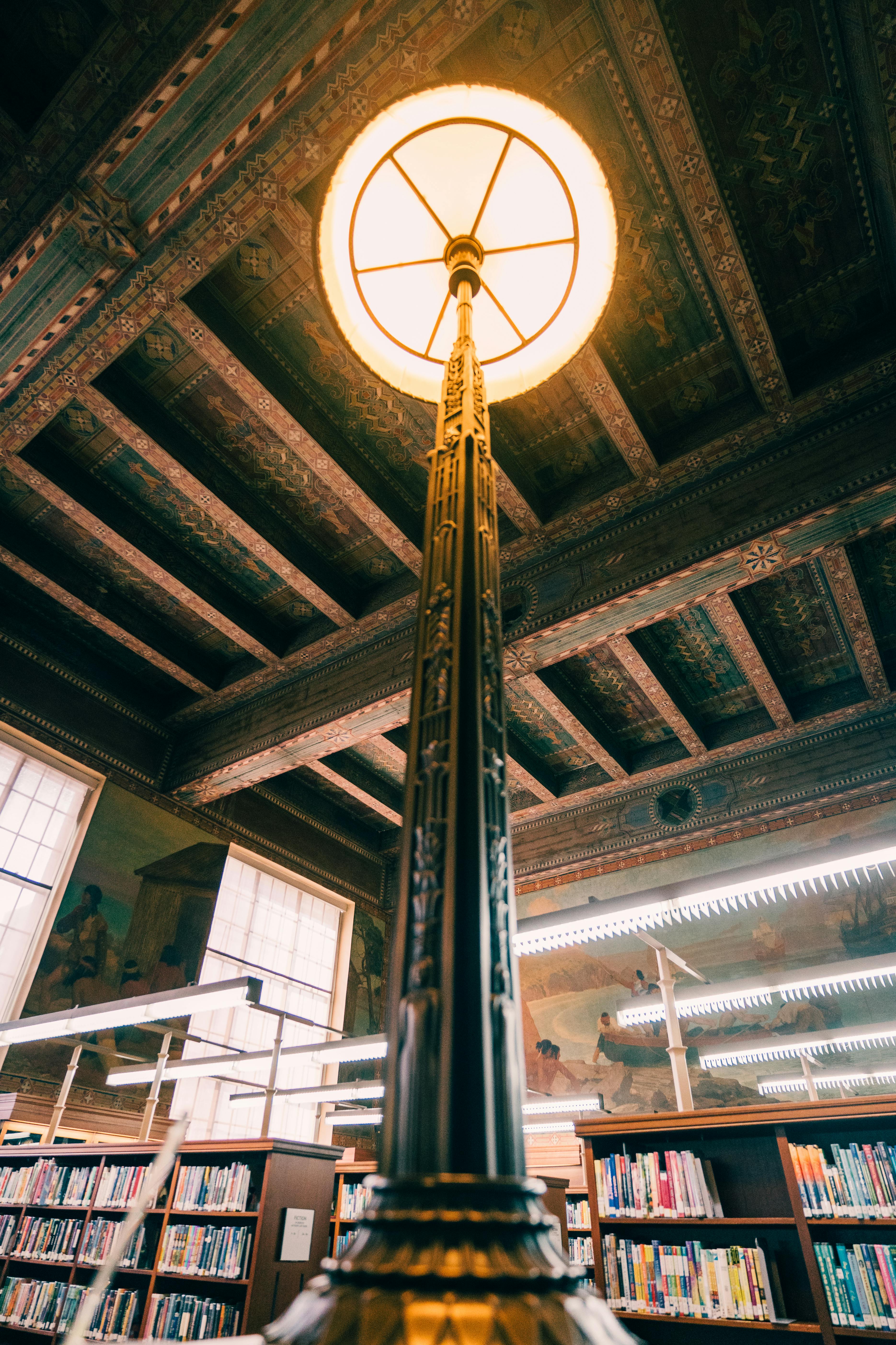 A lamp in a library with books on the shelves · Free Stock Photo