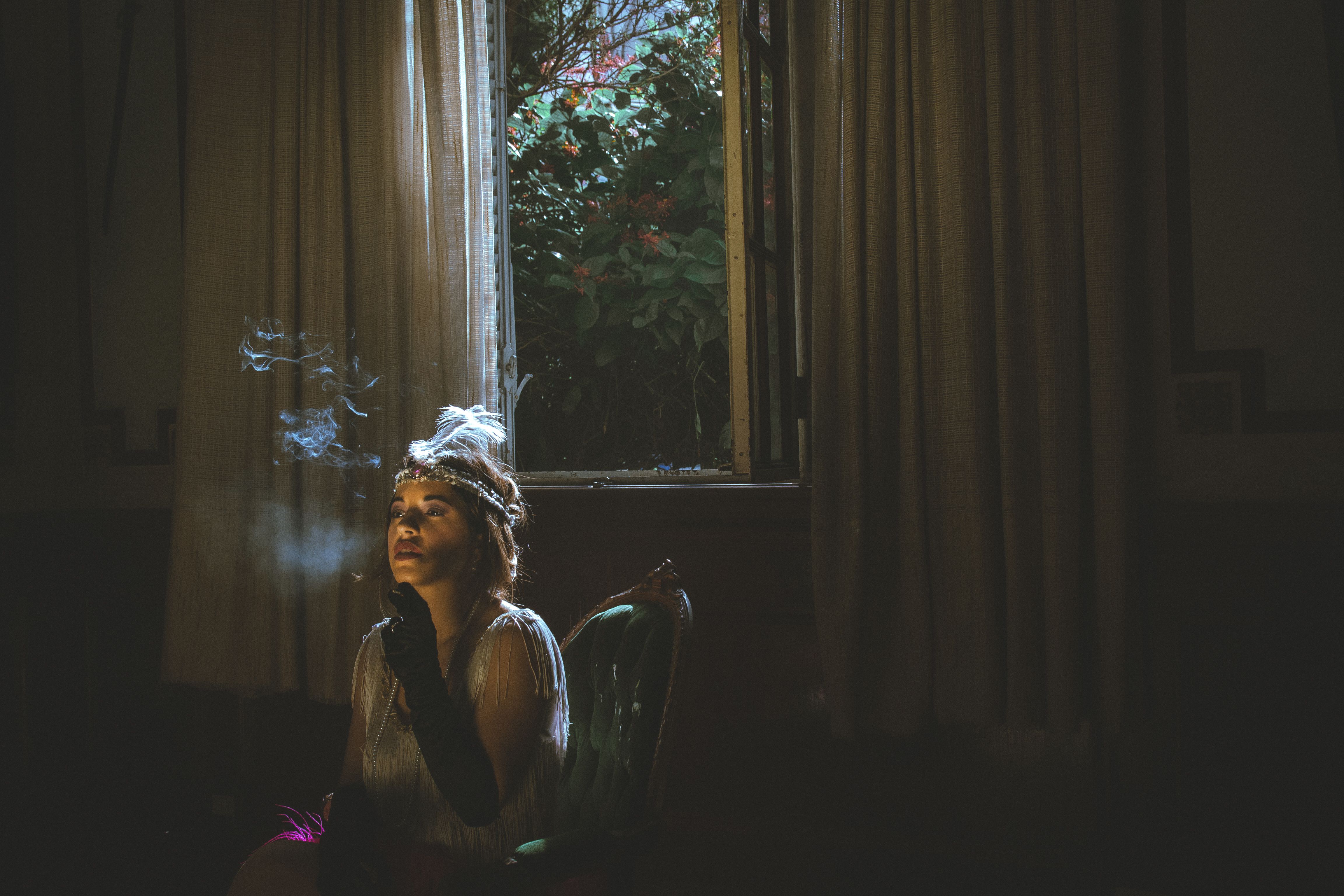 A woman sitting in a chair smoking a cigarette · Free Stock Photo
