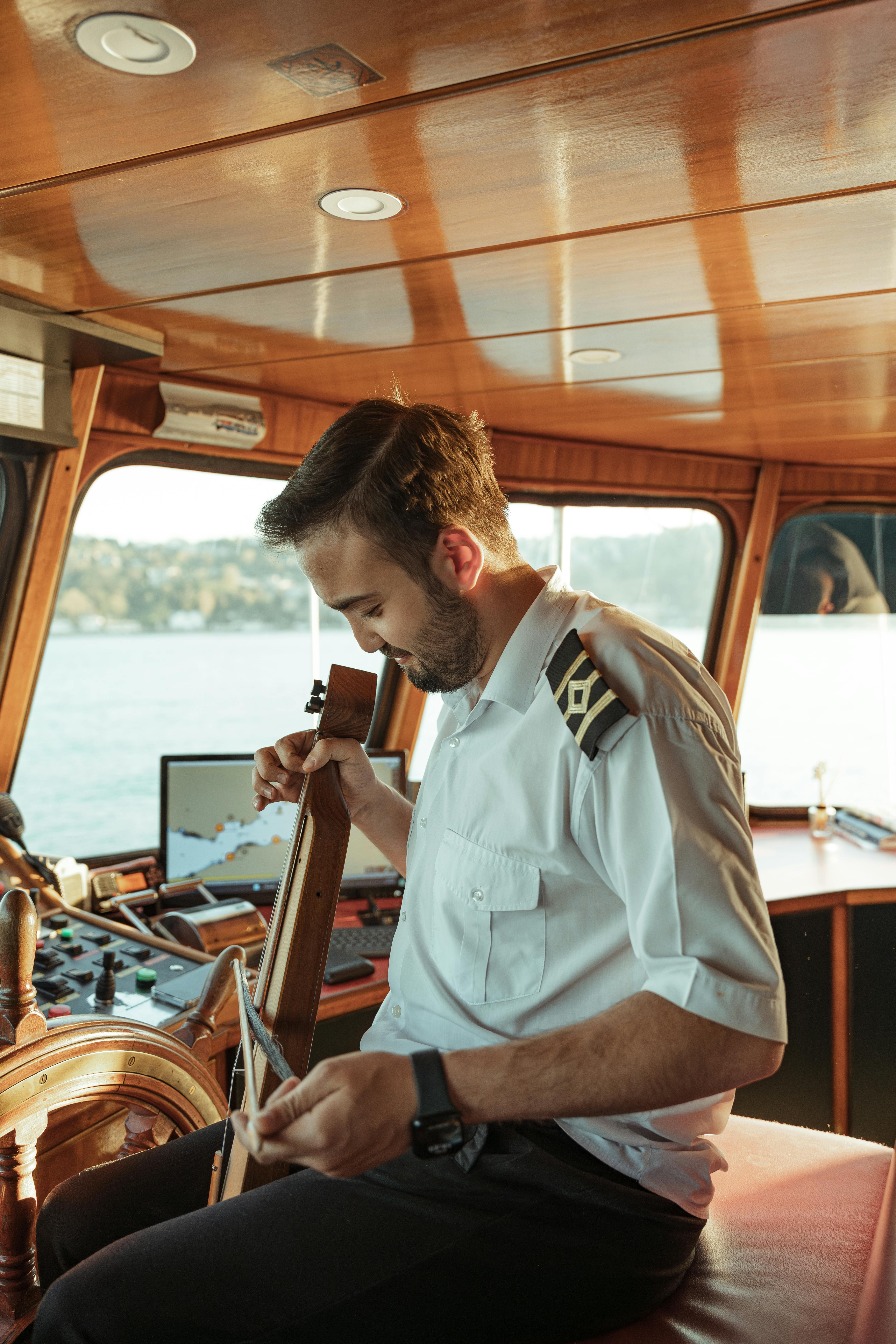 Captain of Vessel Sitting with Musical Instrument · Free Stock Photo