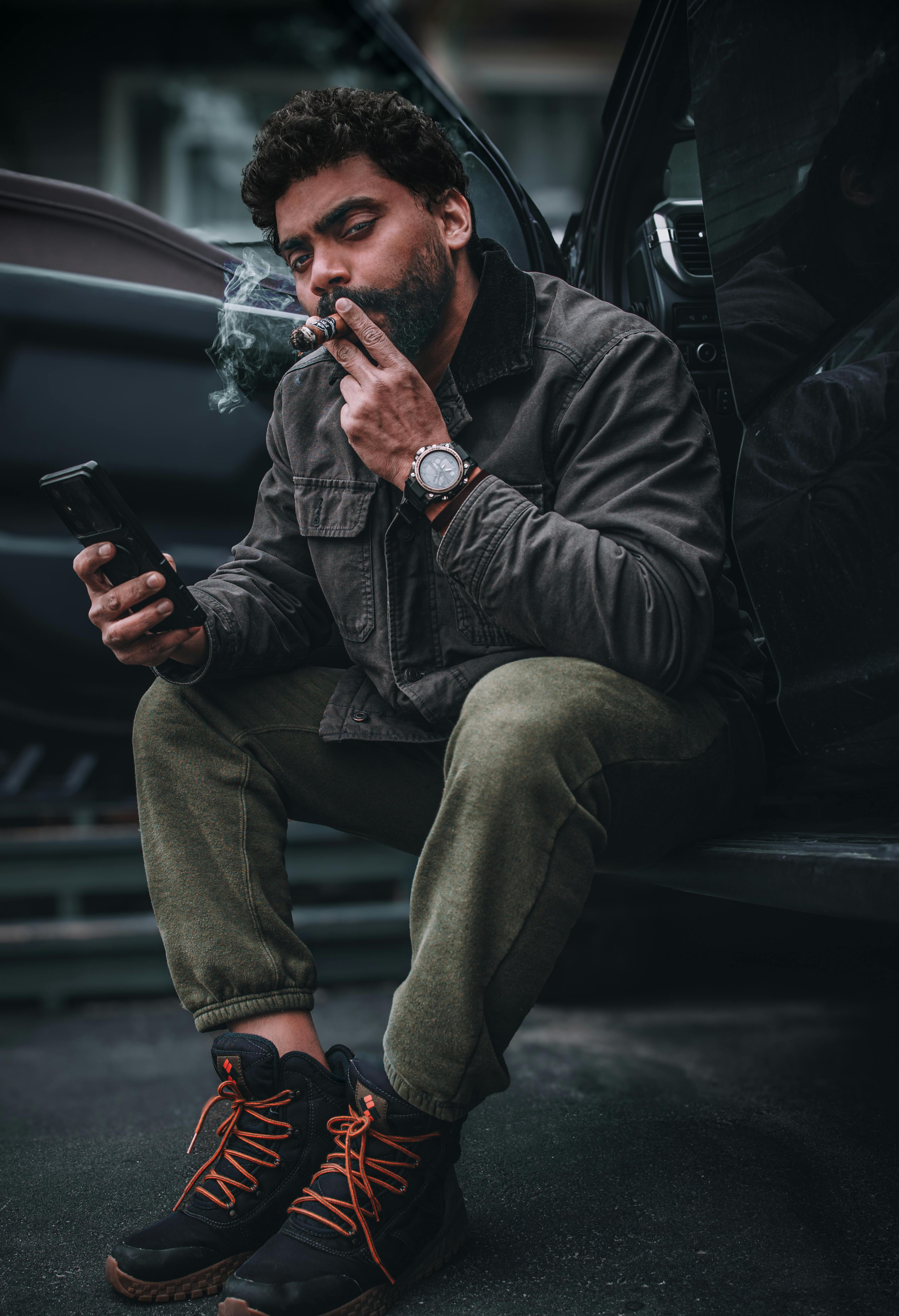 A man sitting on the ground smoking a cigarette · Free Stock Photo