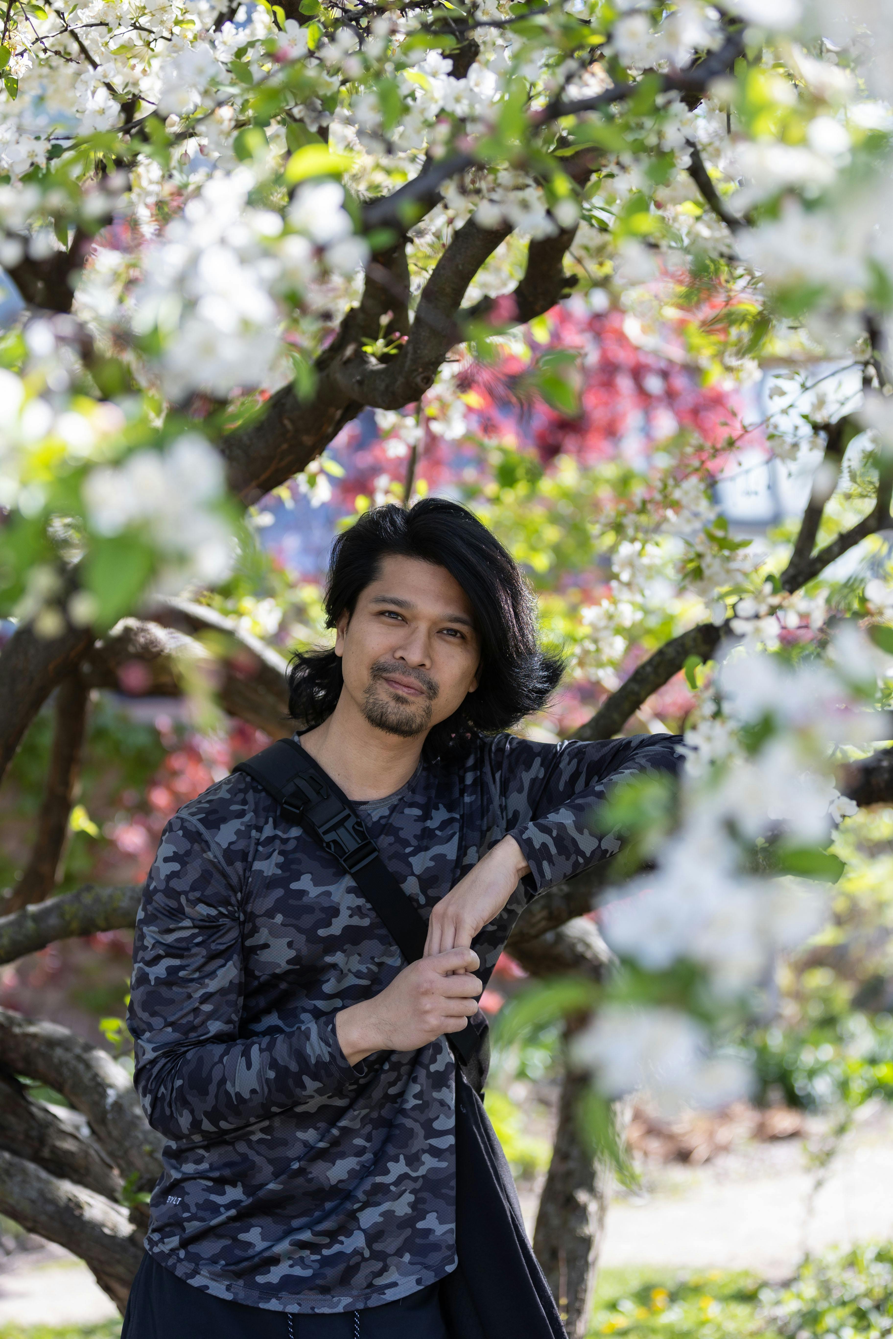 Man in Camouflage Sweatshirt Leaning on Blossoming Tree · Free Stock Photo