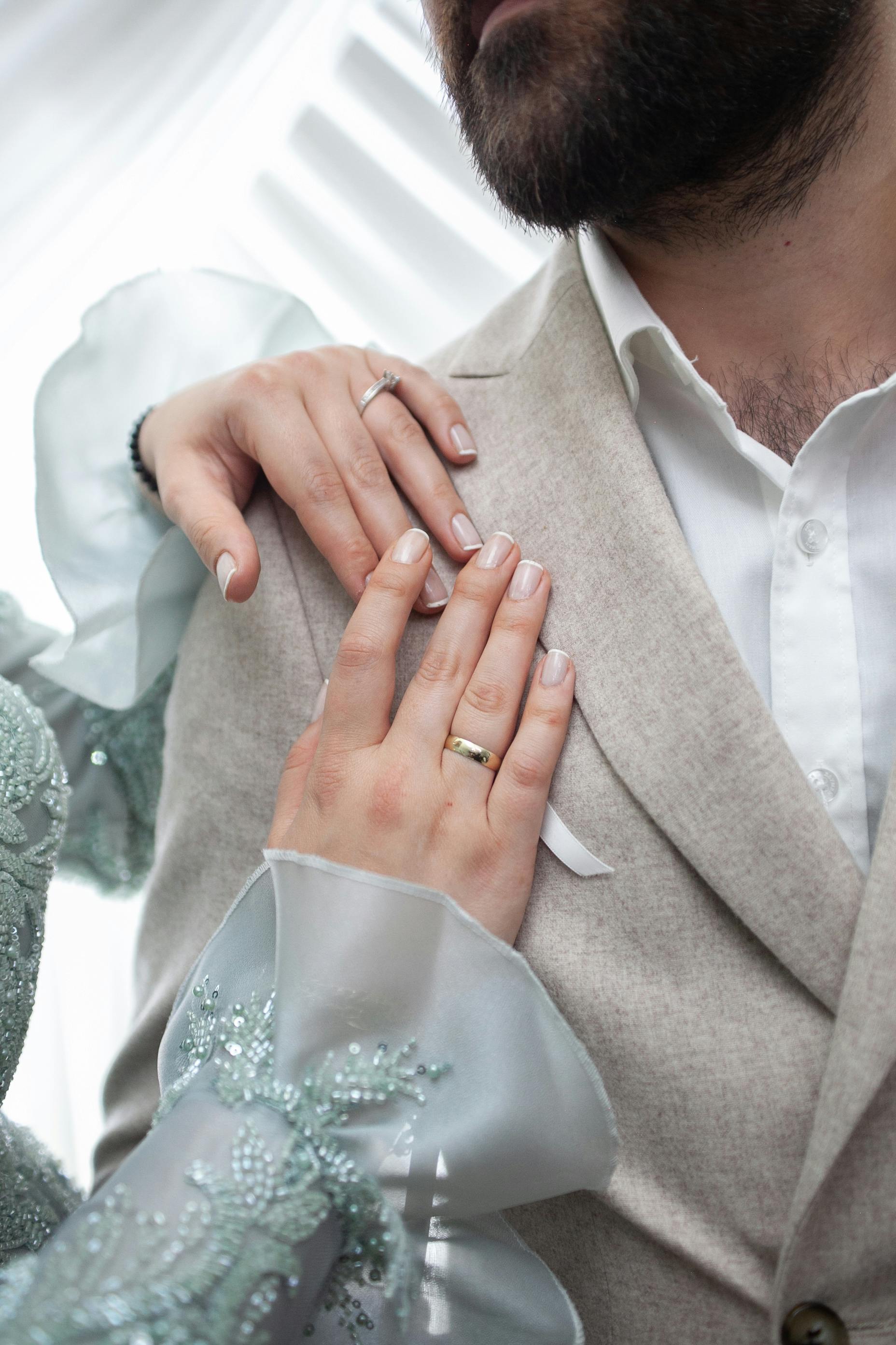 A man and woman are holding hands and touching their wedding rings ...