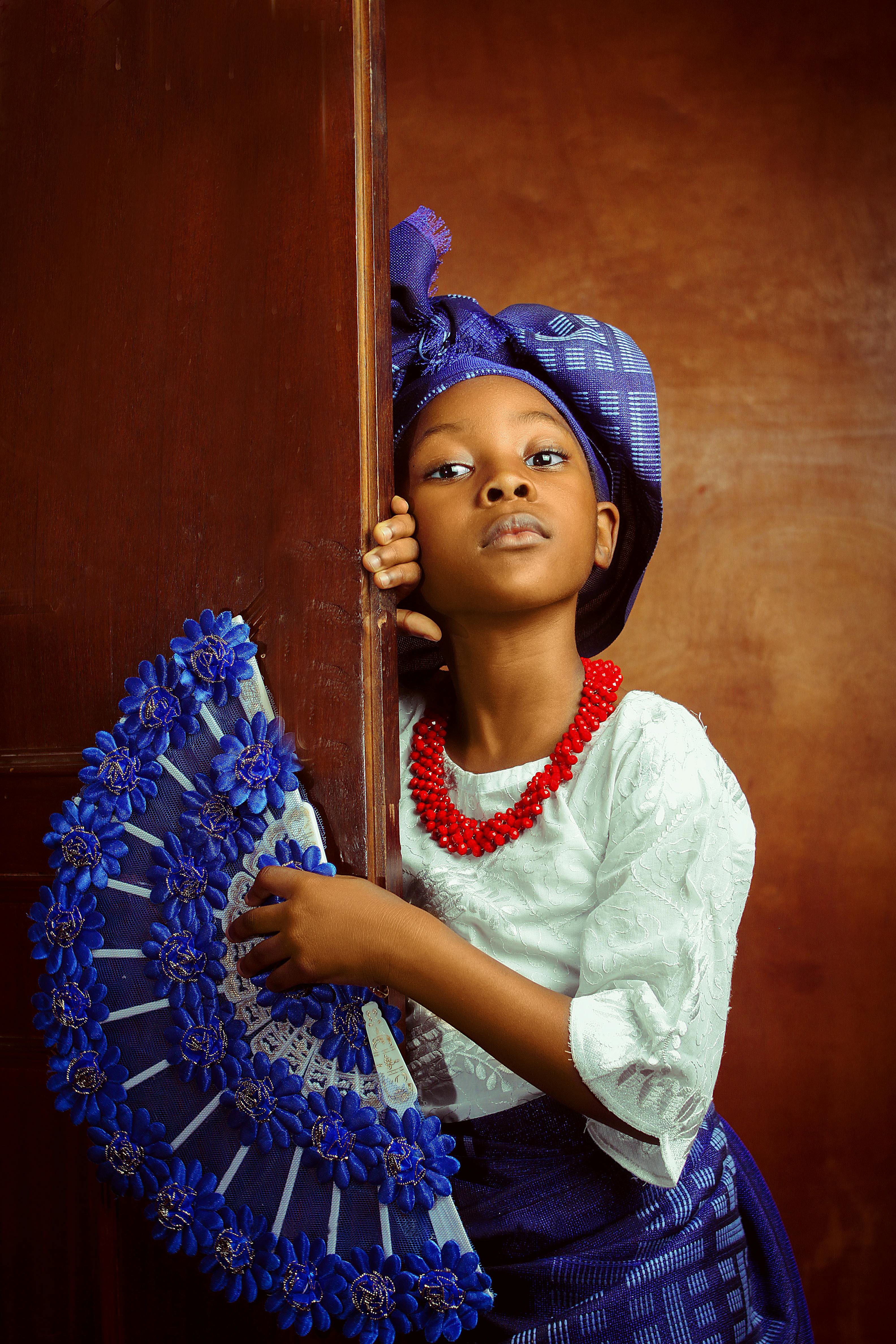 Child Model in Traditional Hat Posing with Fan · Free Stock Photo