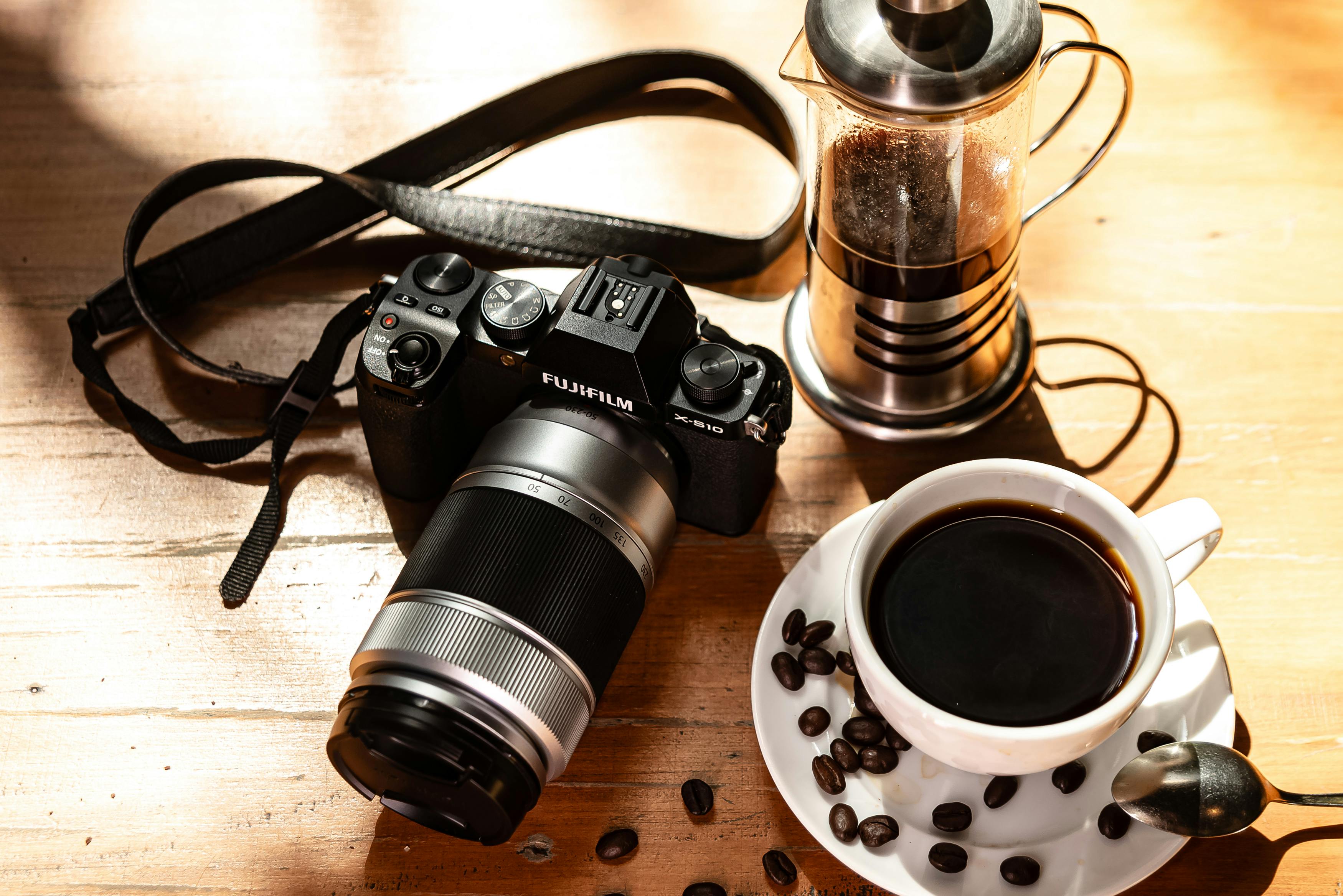 Camera and a Cup of Coffee on a Table · Free Stock Photo