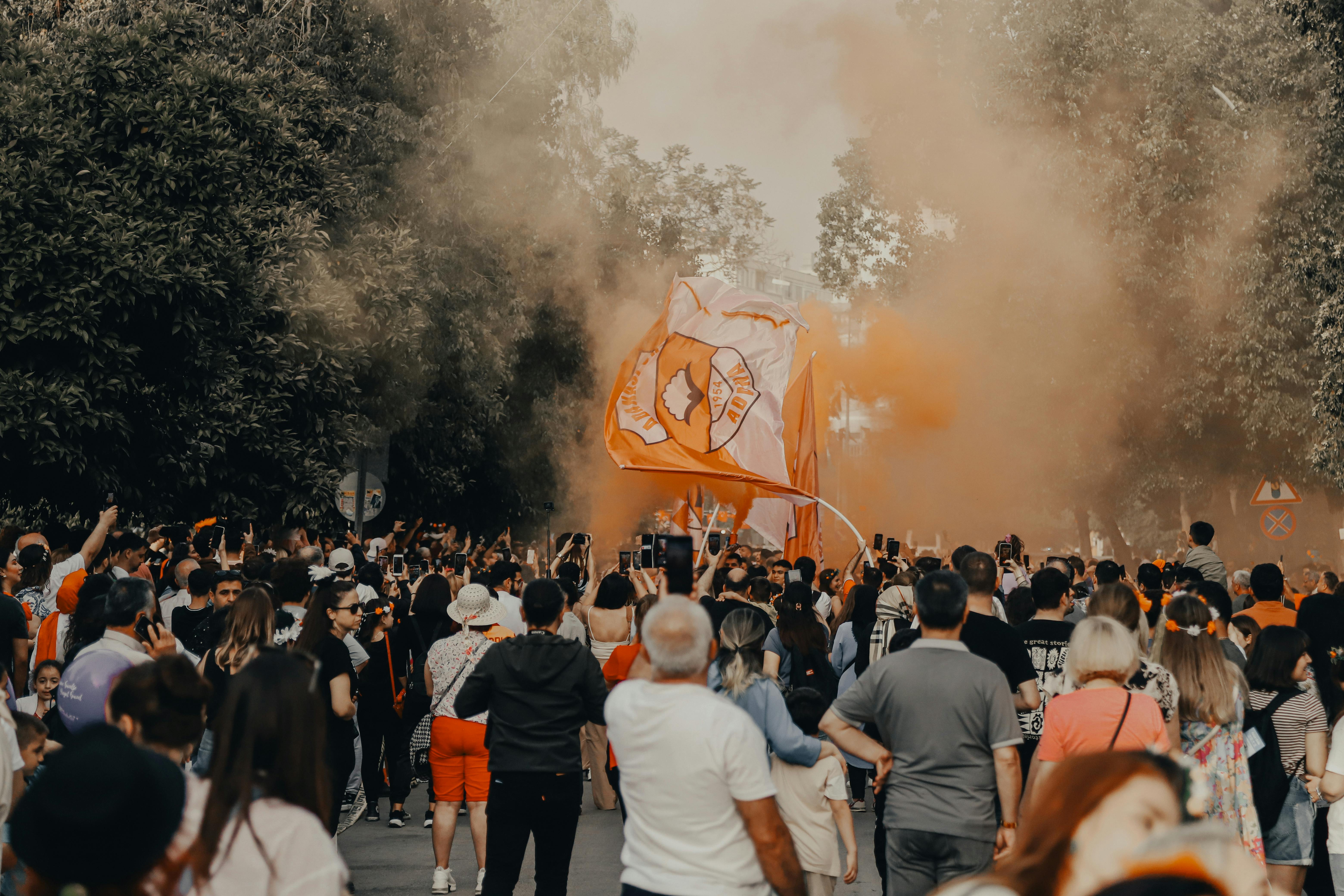 A crowd of people with orange smoke in the air · Free Stock Photo