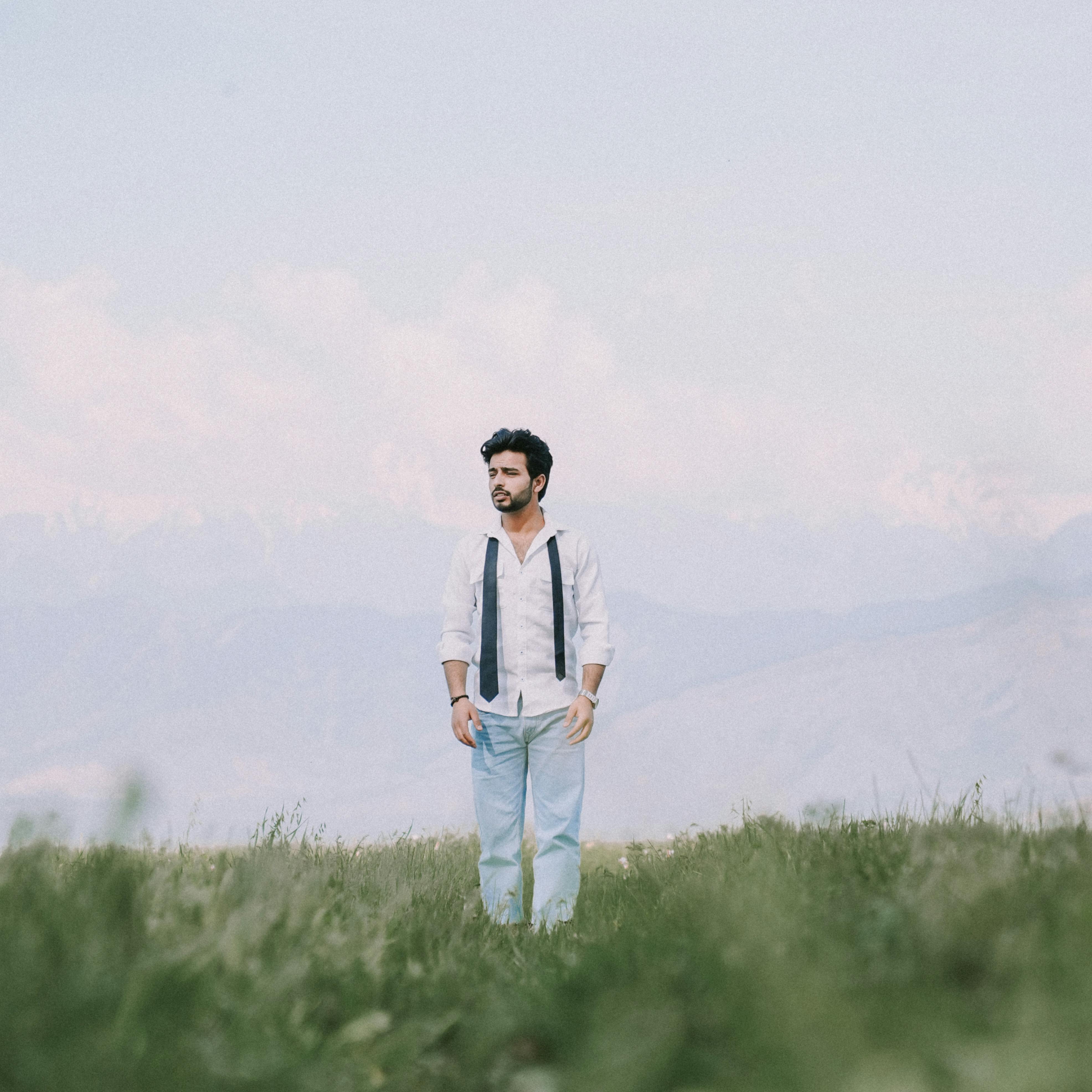 Man Standing in Field under Cloudy Sky · Free Stock Photo