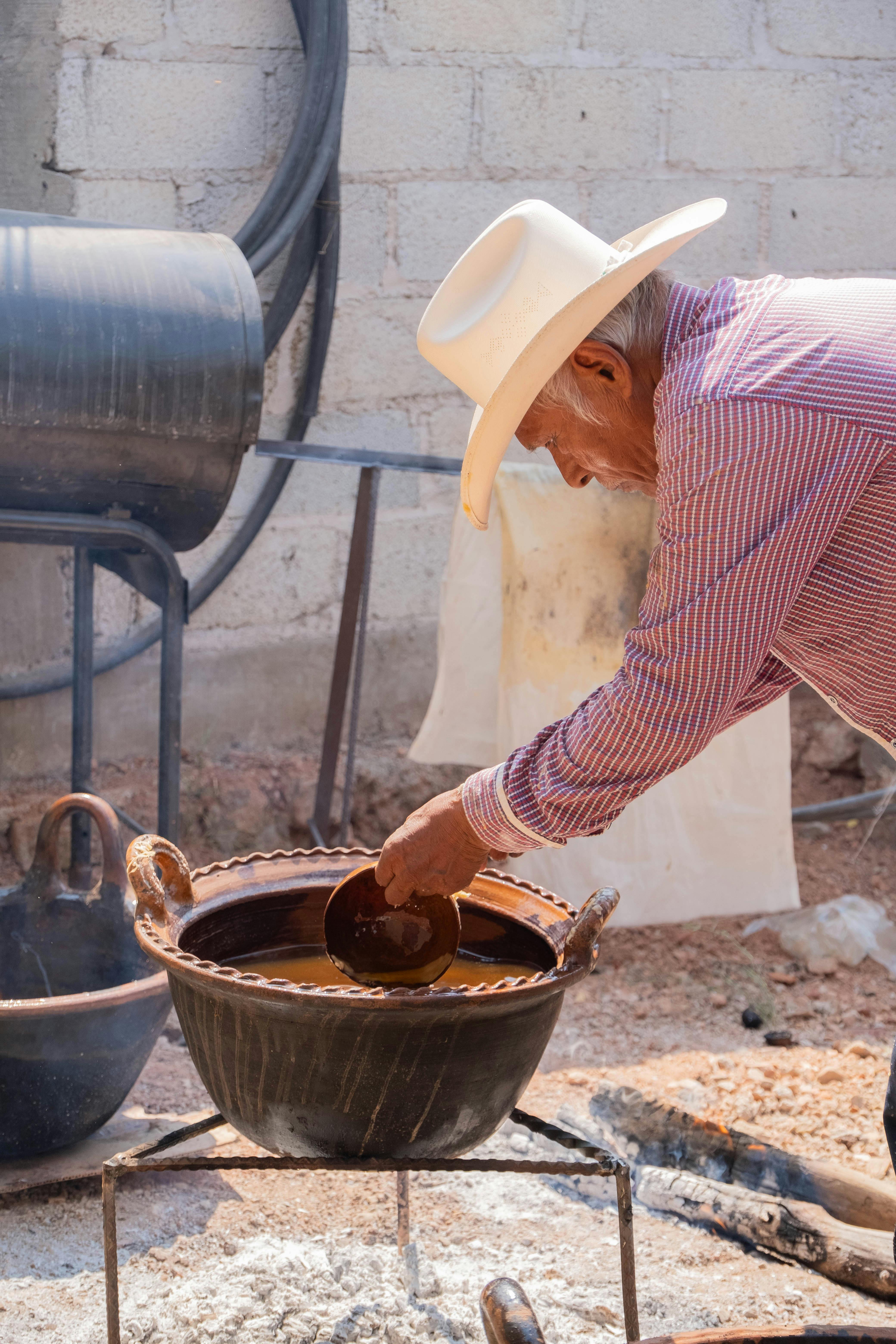 Senior Man Pouring Liquid into a Cauldron Standing Outdoors · Free ...