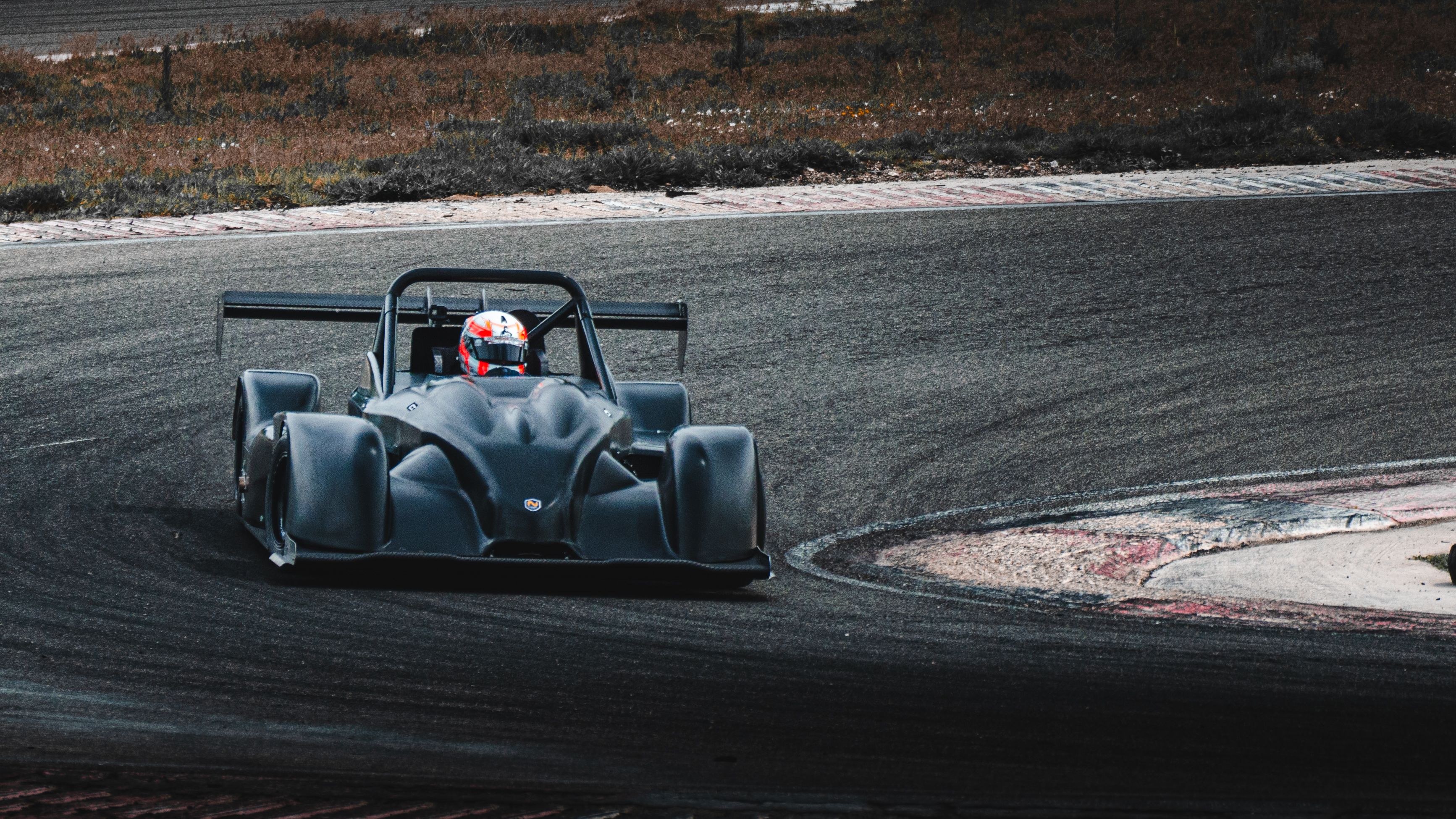 A race car driving on a track with a person in the car · Free Stock Photo
