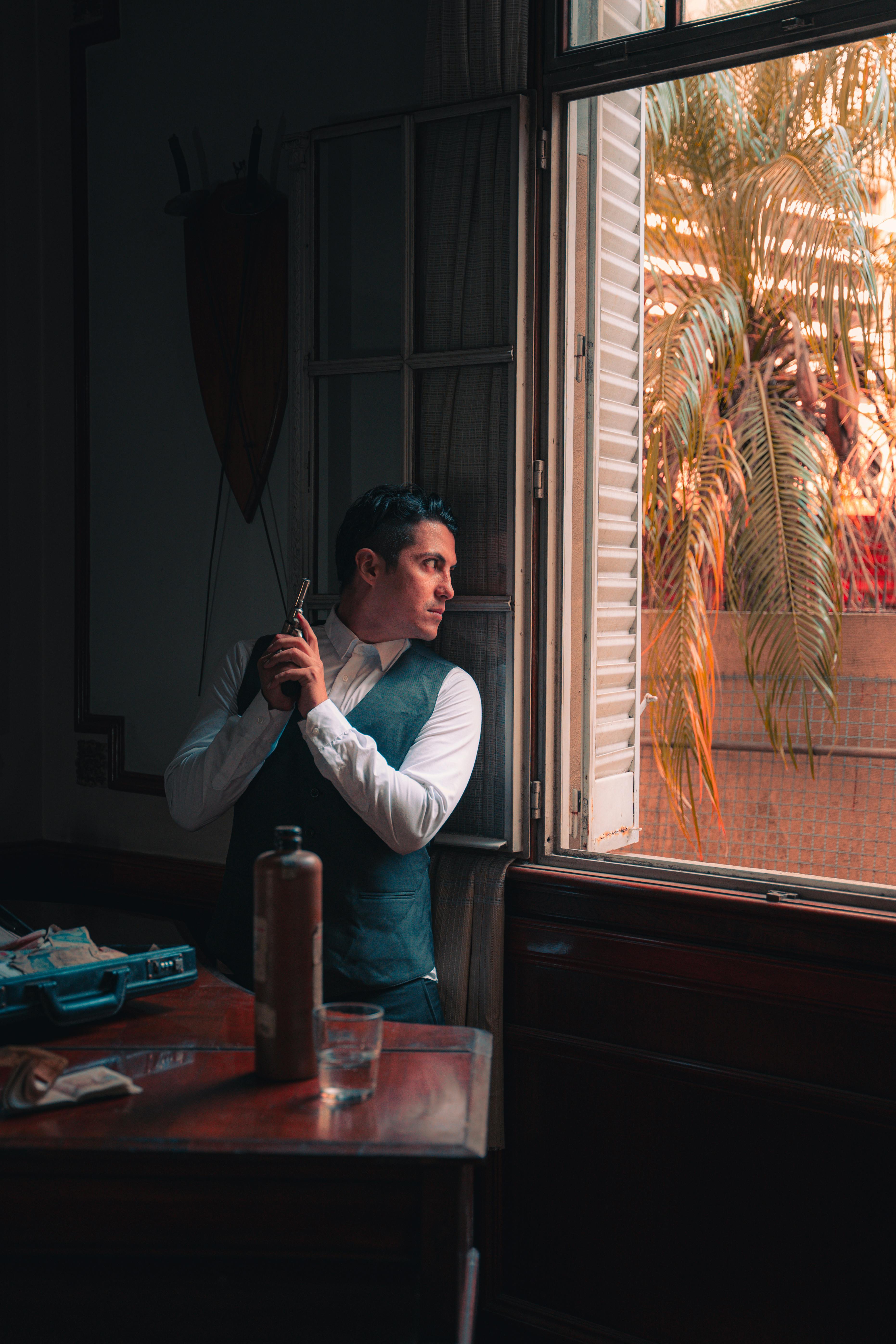 Man with a Gun Lurking by the Window · Free Stock Photo