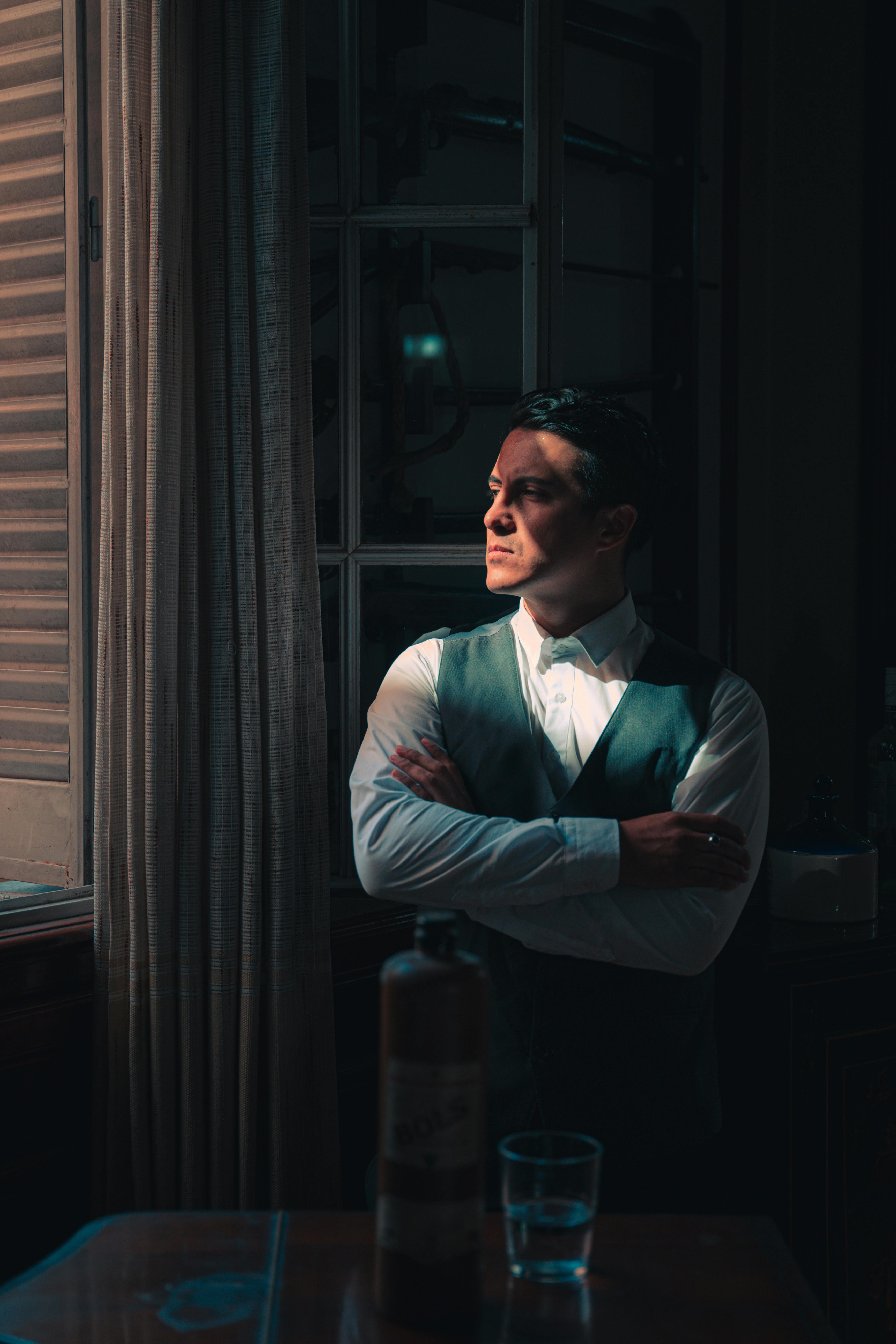 Man with His Arms Crossed Standing by the Window · Free Stock Photo
