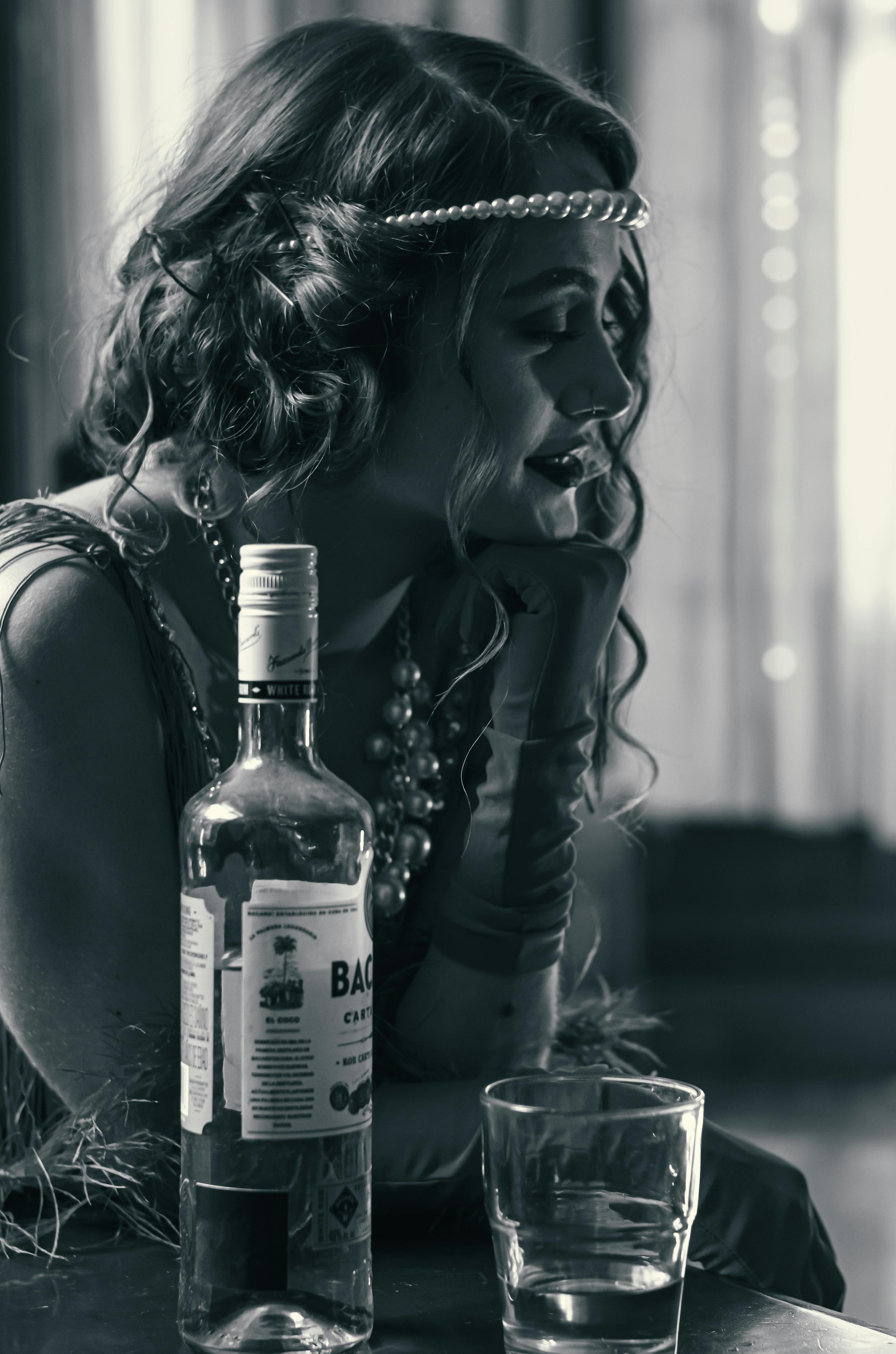 Woman in Flapper Dress Sitting at Table with Bottle of Rum · Free Stock ...