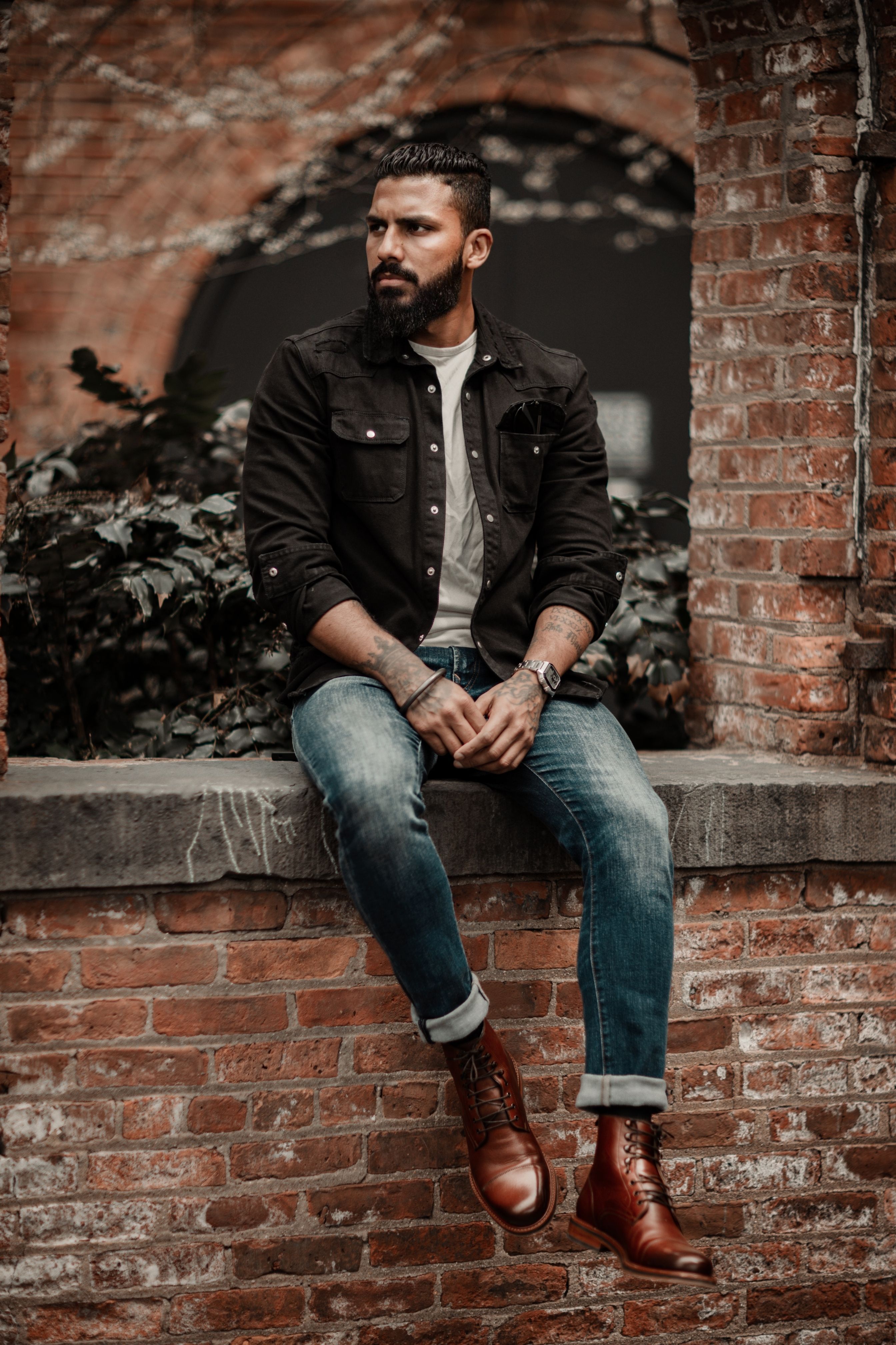 Man in Denim Jacket Sitting on Brick Wall · Free Stock Photo