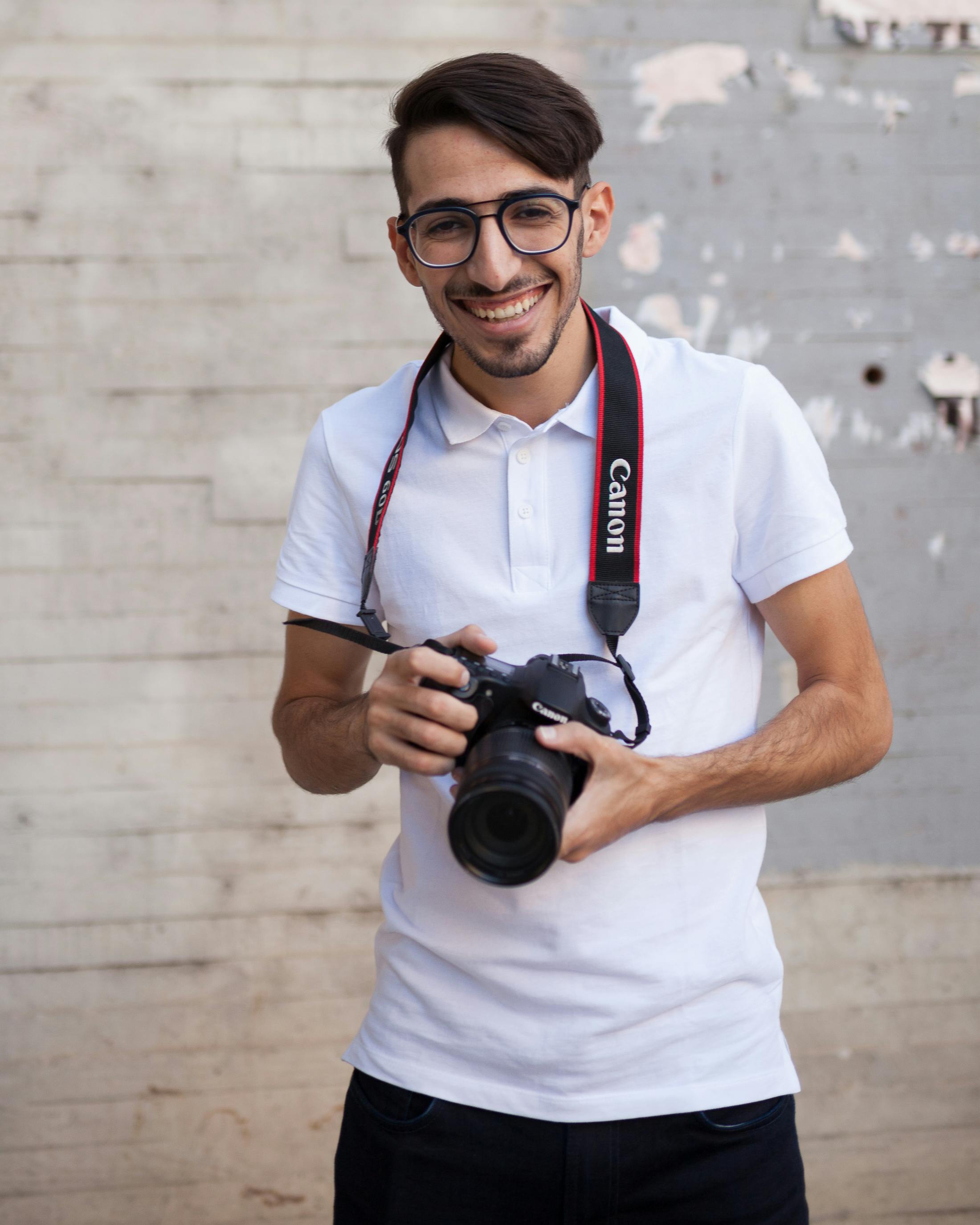 Smiling Man Standing with Camera · Free Stock Photo