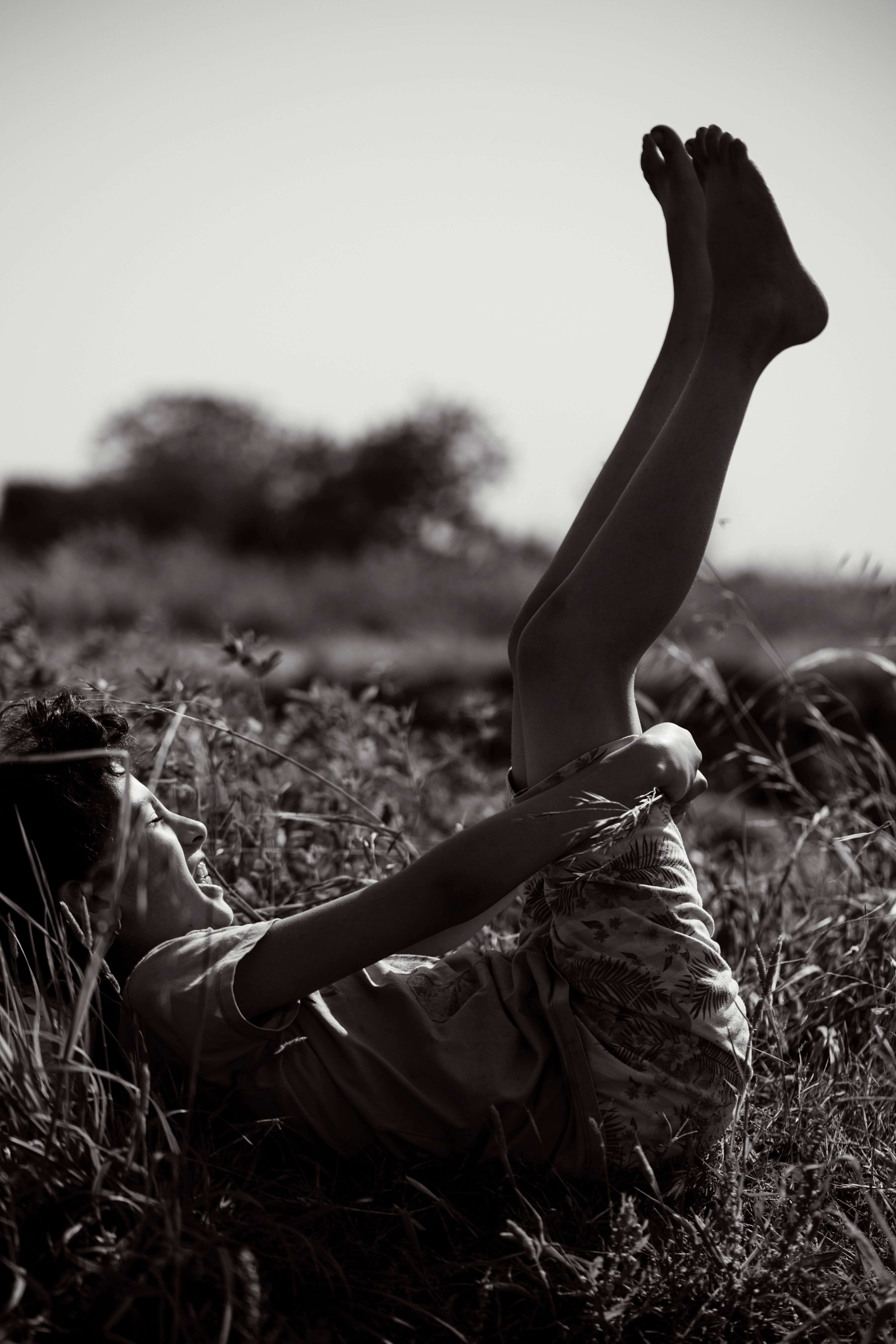 A black and white photo of a person laying on their back in the grass ...