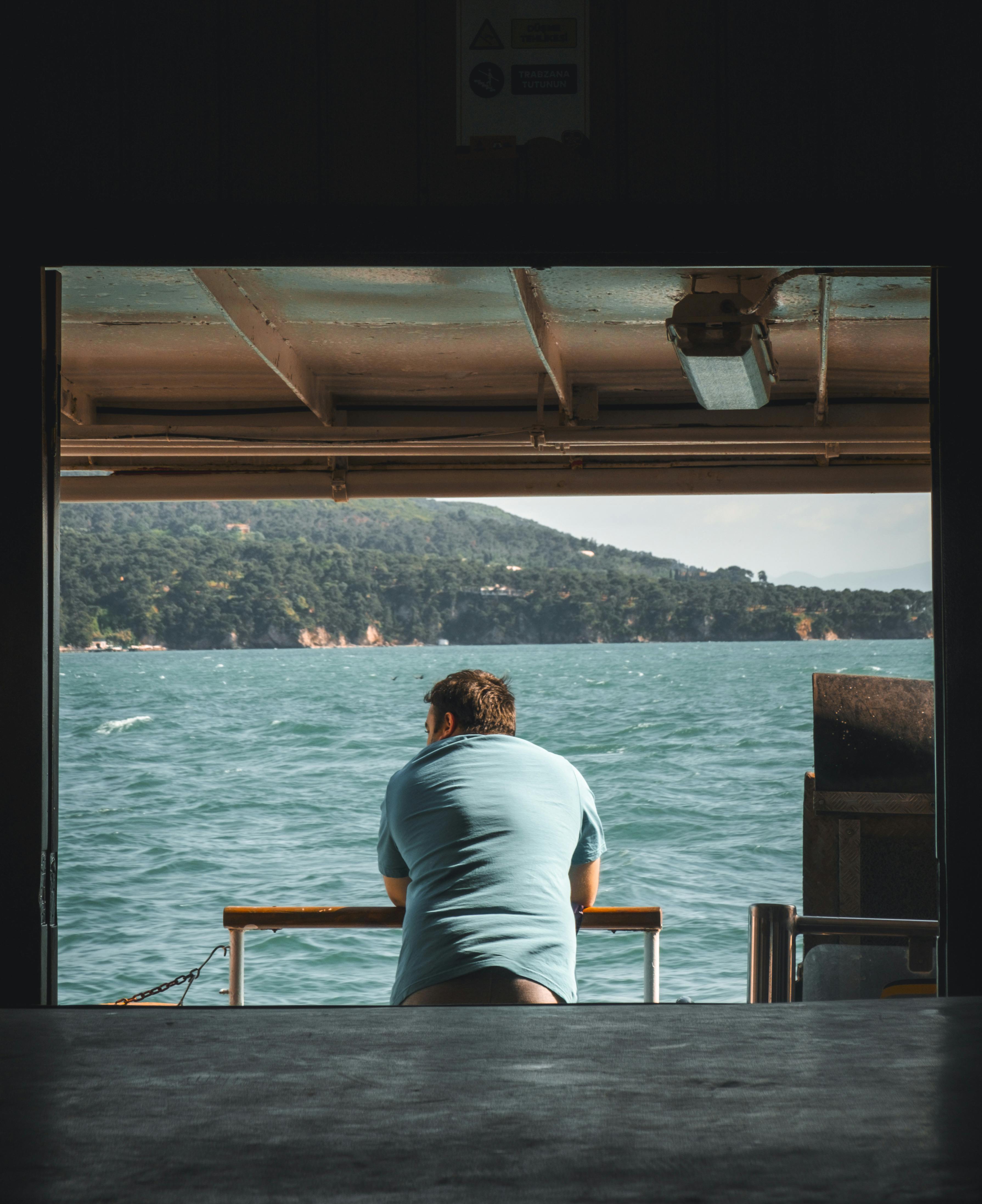 Man Leaning on Railing on Lakeshore · Free Stock Photo