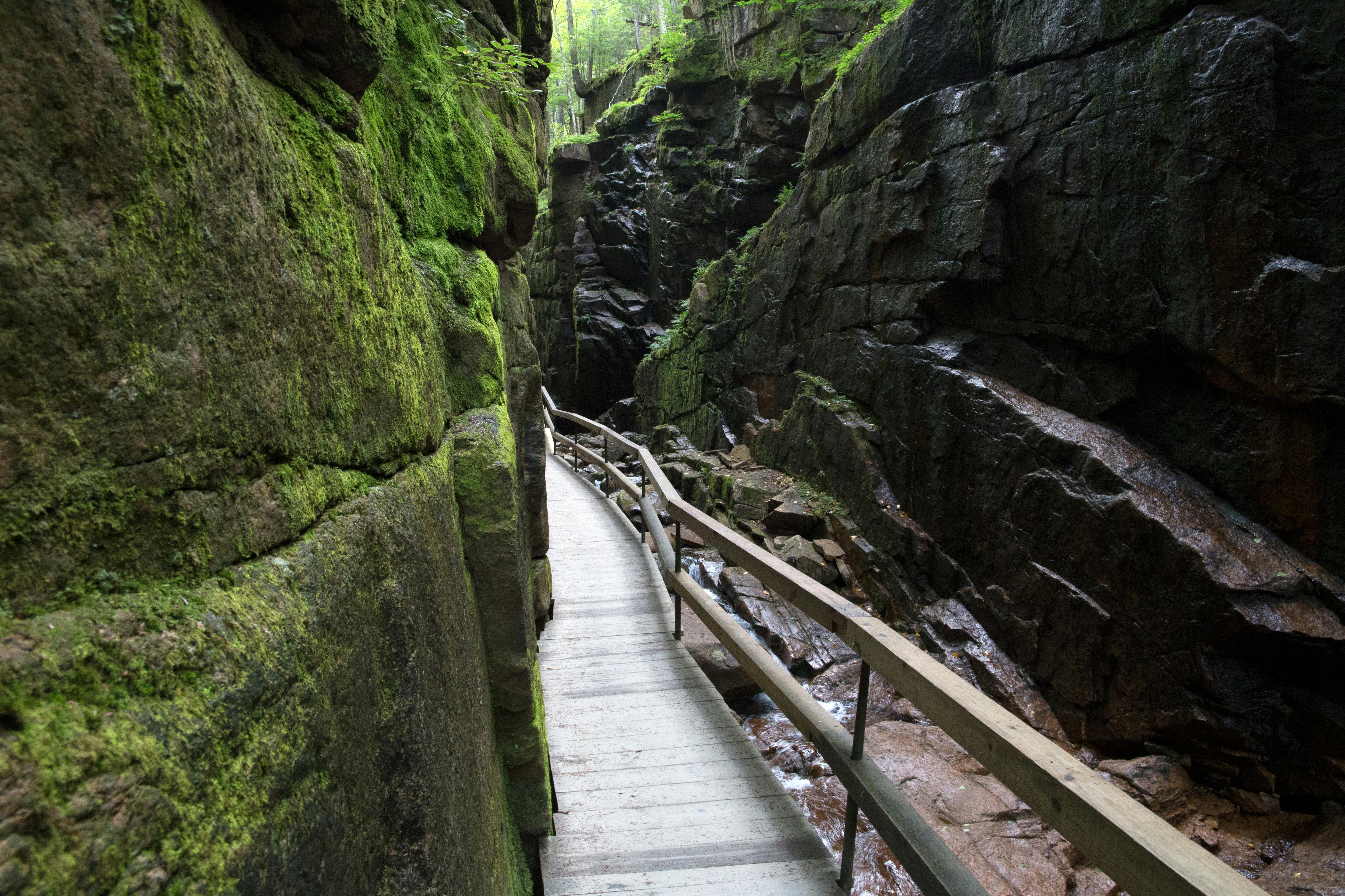 Gray Wooden Bridge Between Two Mossy Rock Formation · Free Stock Photo