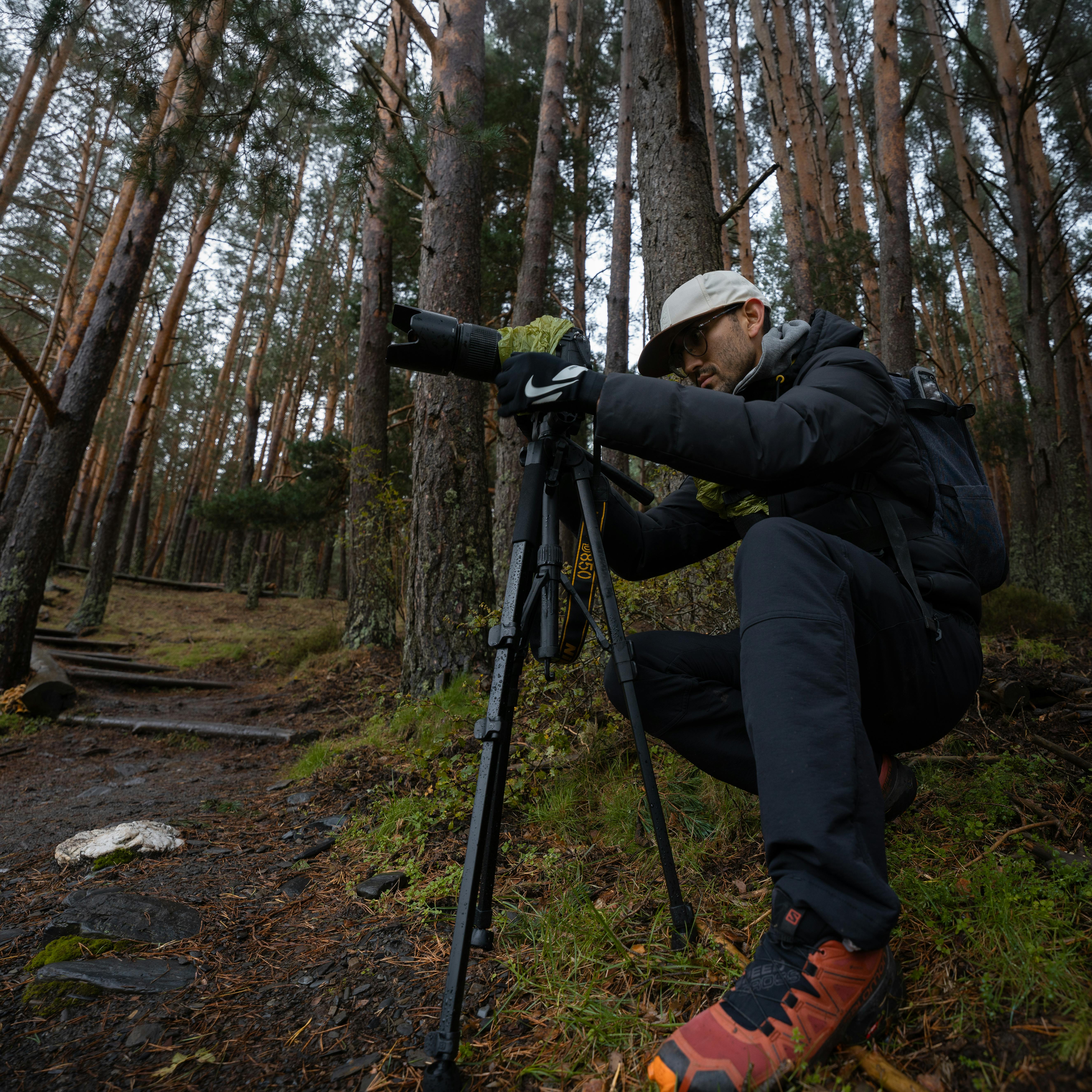 Photographer Crouching with Tripod in Forest · Free Stock Photo
