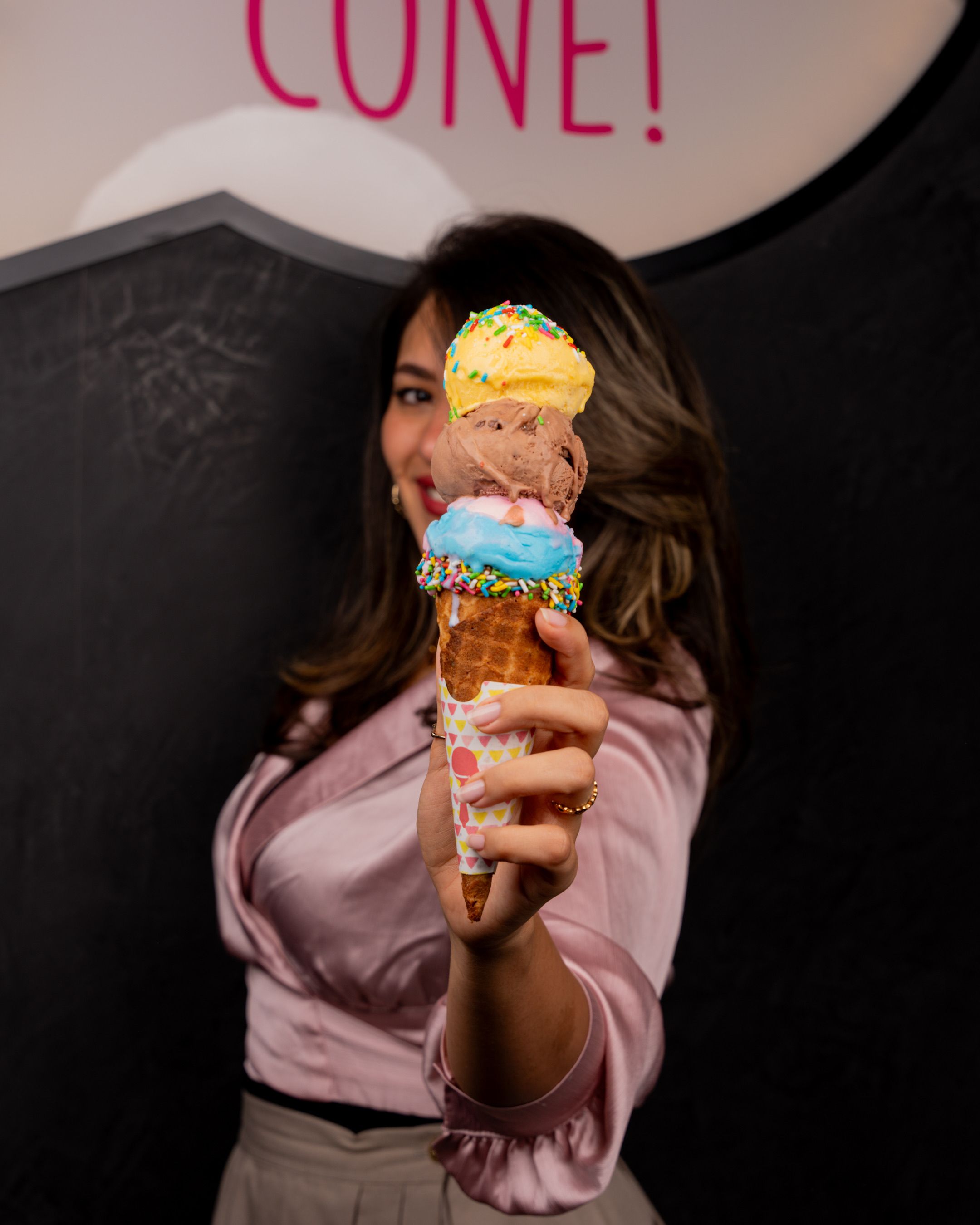 A woman holding up a cone with three different flavors · Free Stock Photo
