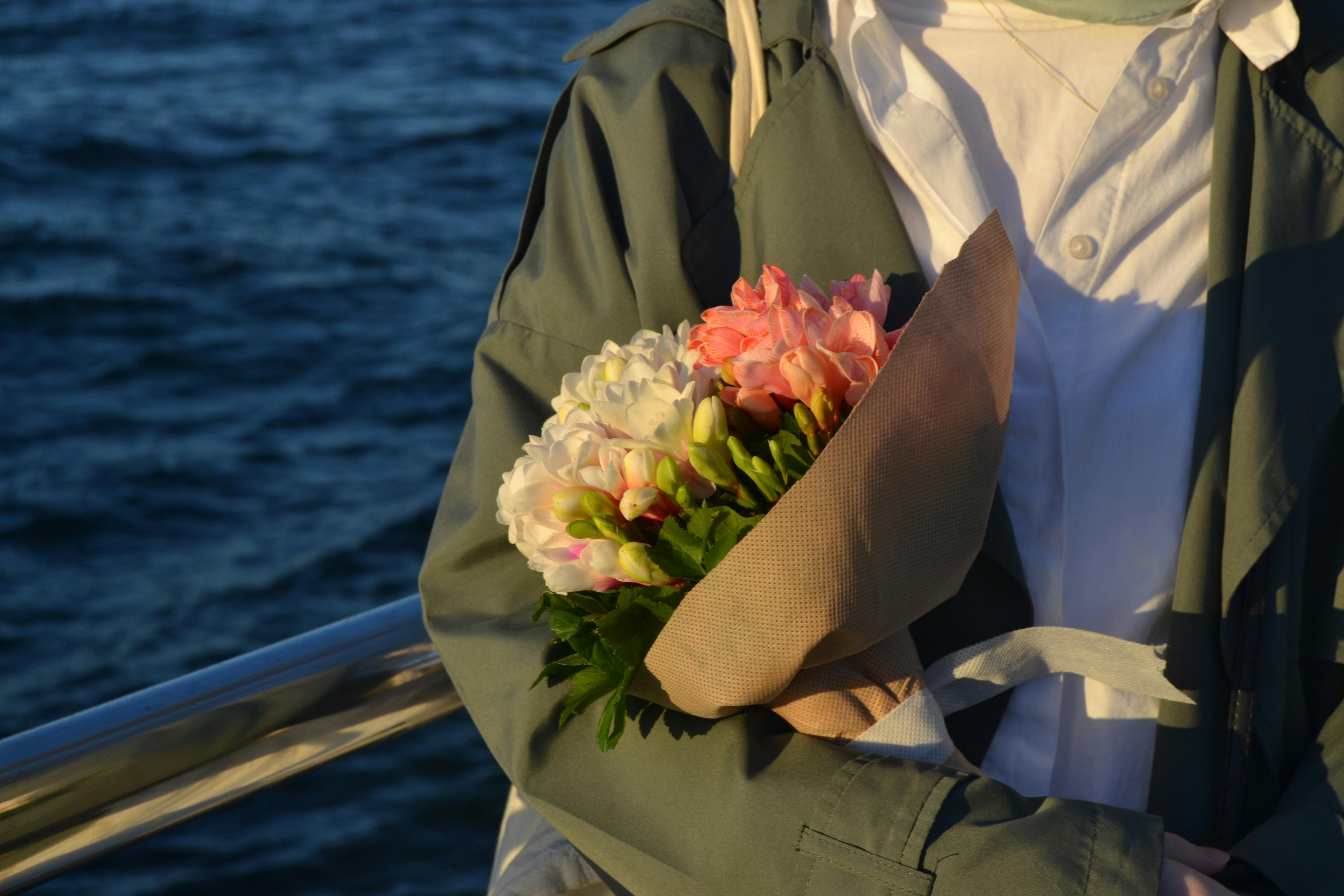 A person holding a bouquet of flowers on a boat · Free Stock Photo