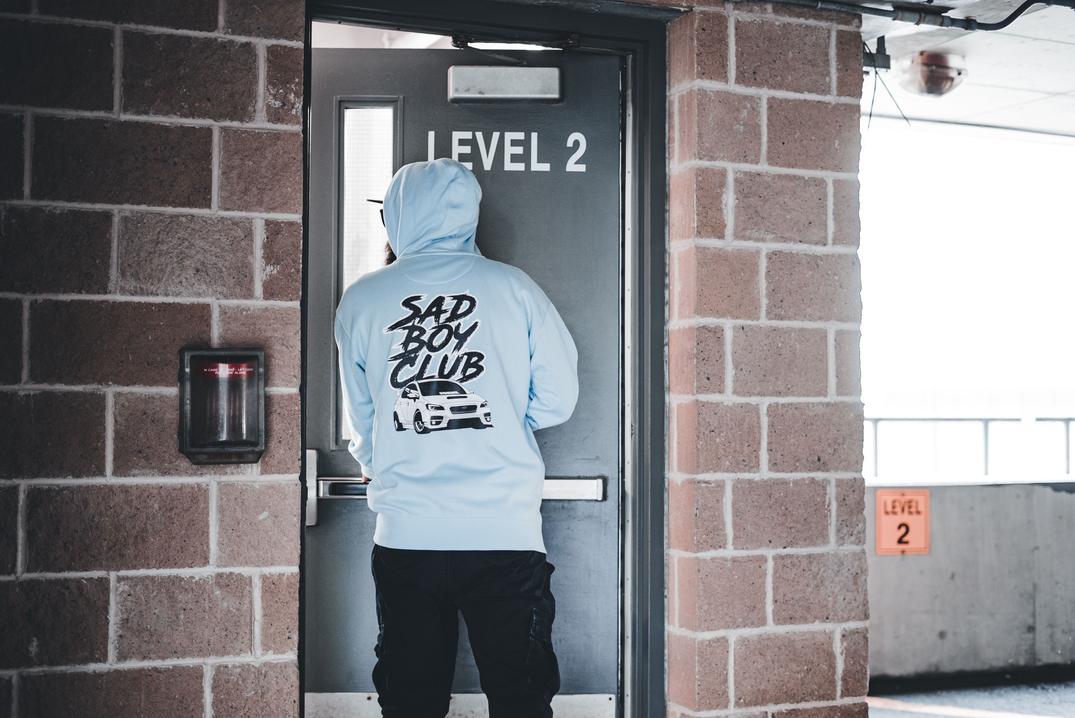 Person in Blue Hoodie with Sad Boy Club Script in Door · Free Stock Photo