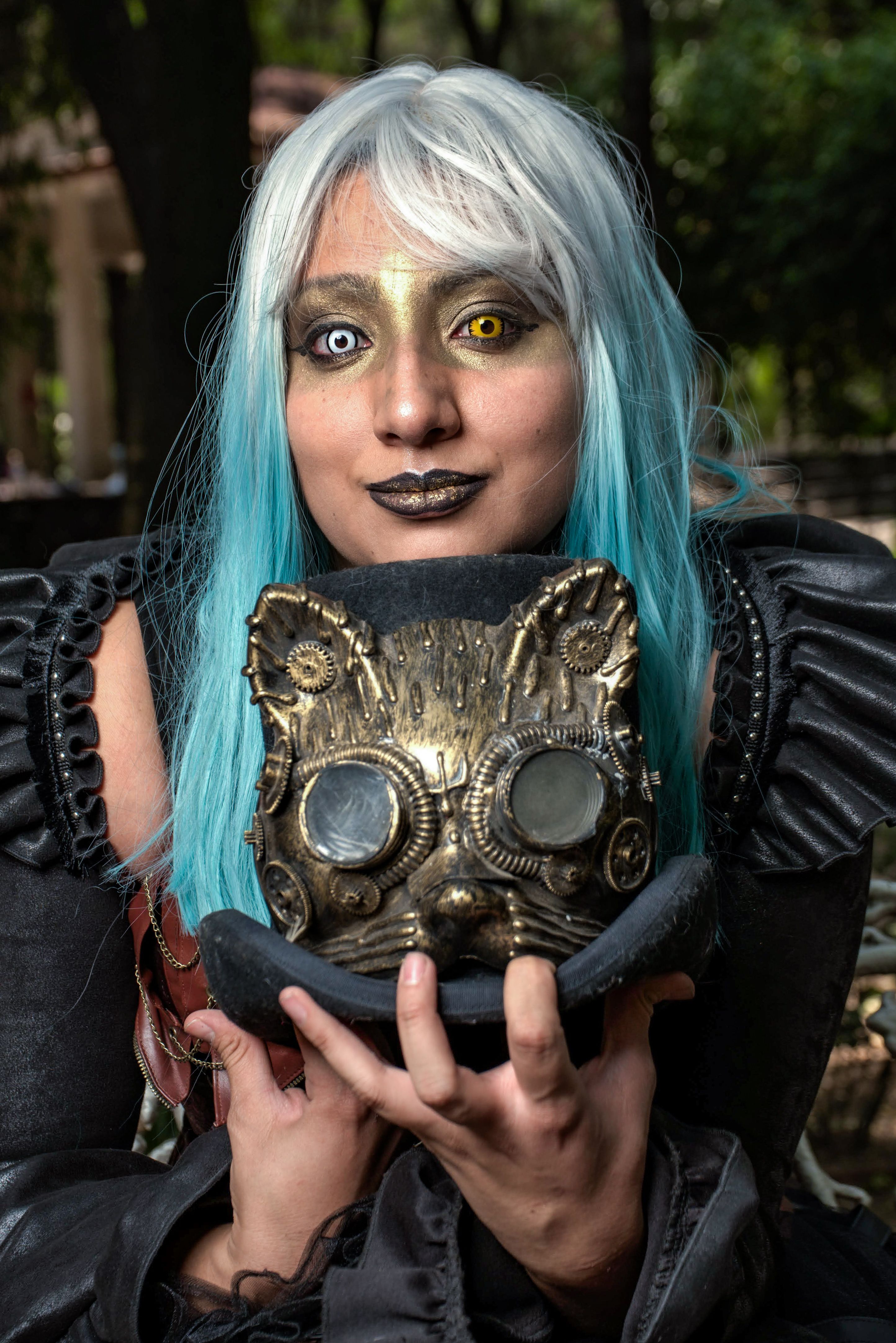 A woman with blue hair and white makeup holding a gold mask · Free ...