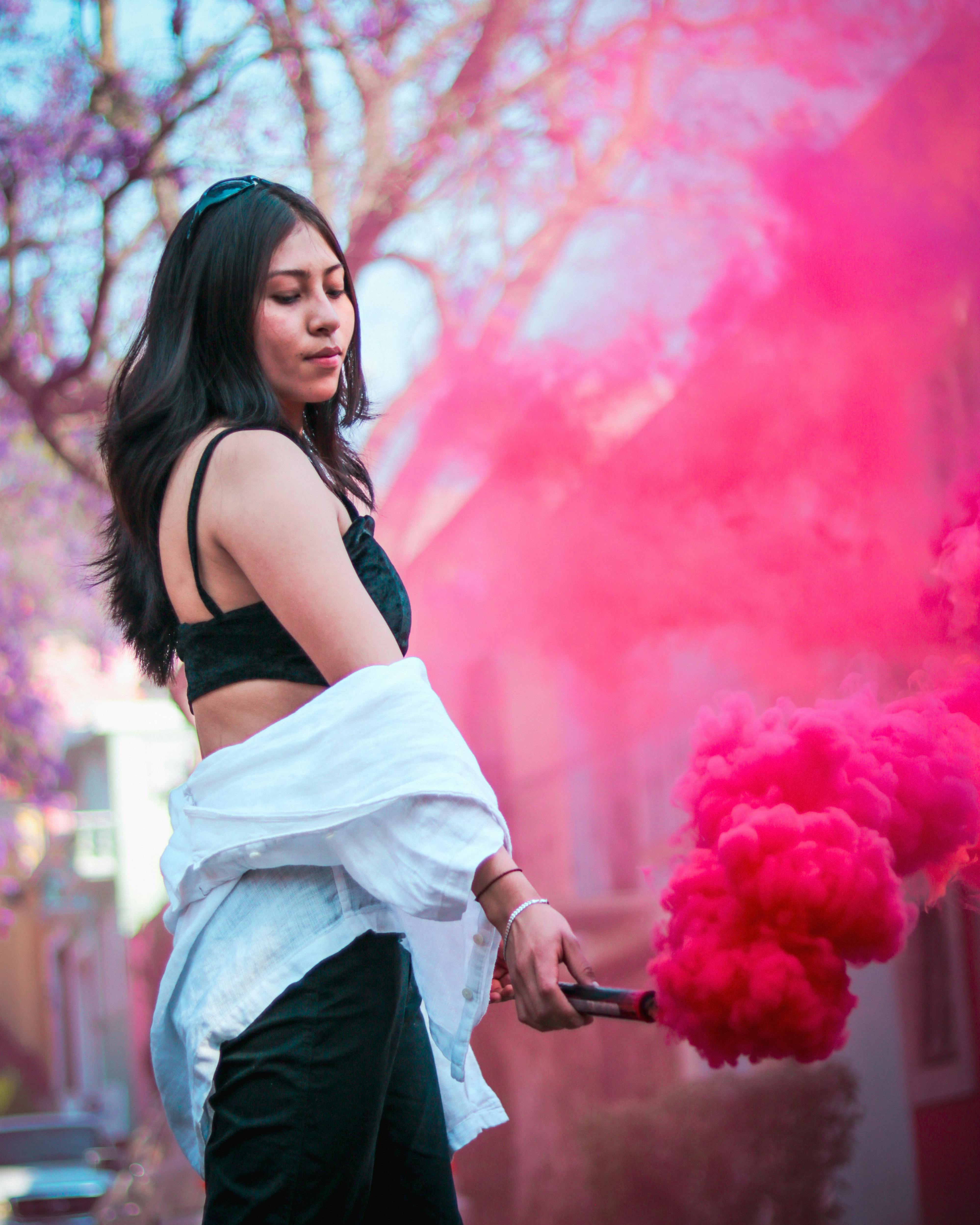 A woman holding pink smoke bombs in her hand · Free Stock Photo
