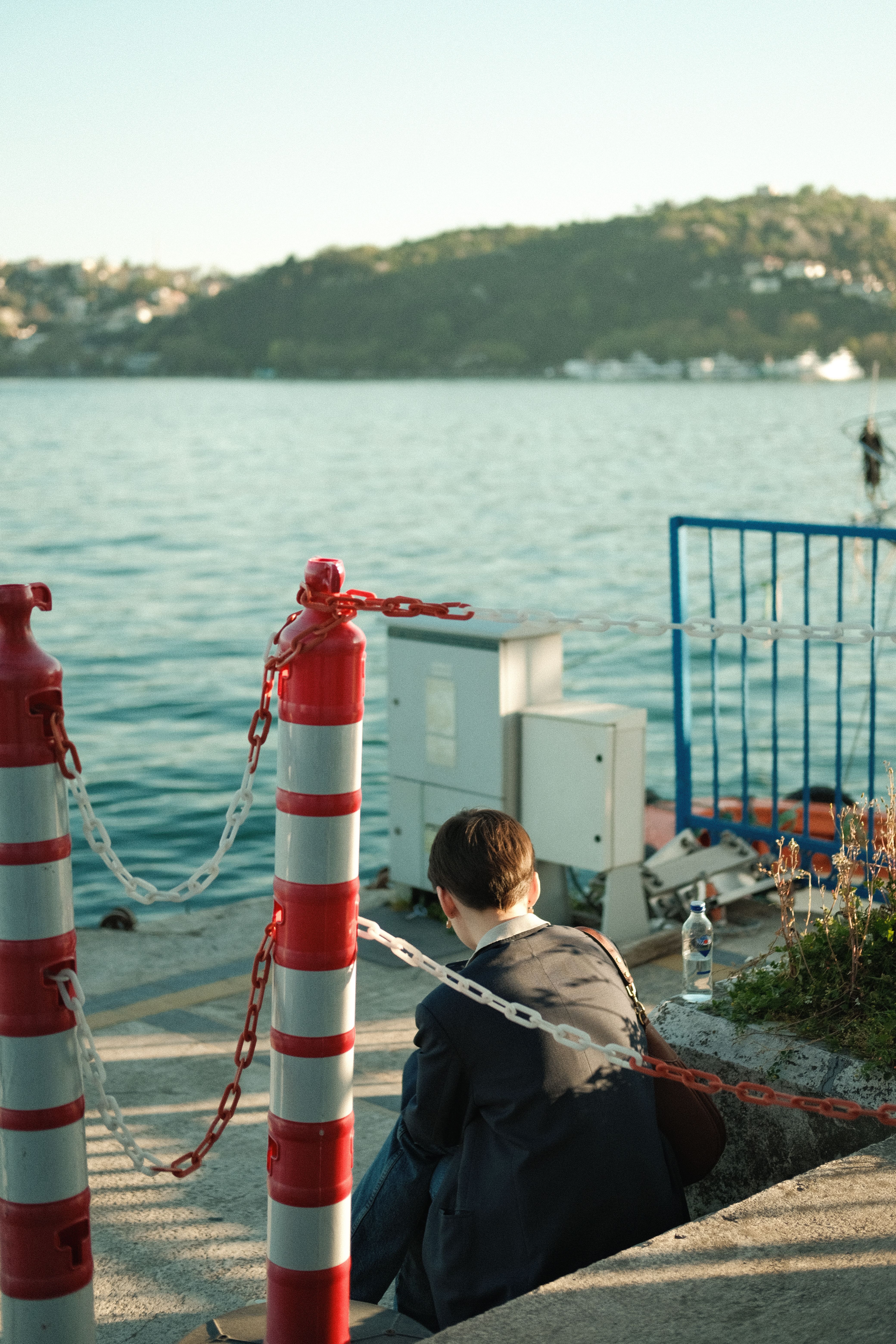 Red Striped Balustrade, and a Man Sitting on a Pier · Free Stock Photo
