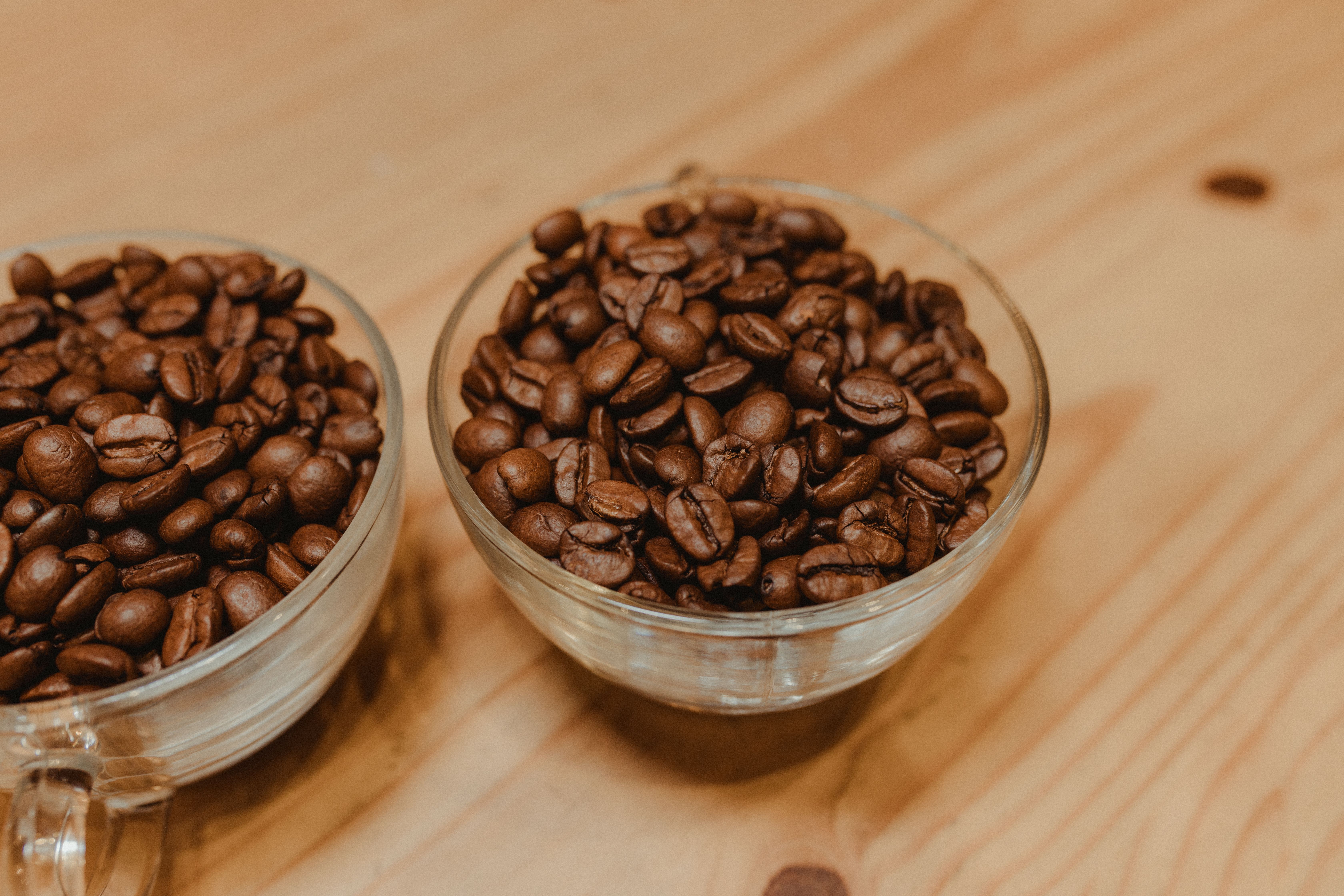 Two cups of coffee beans on a wooden table · Free Stock Photo