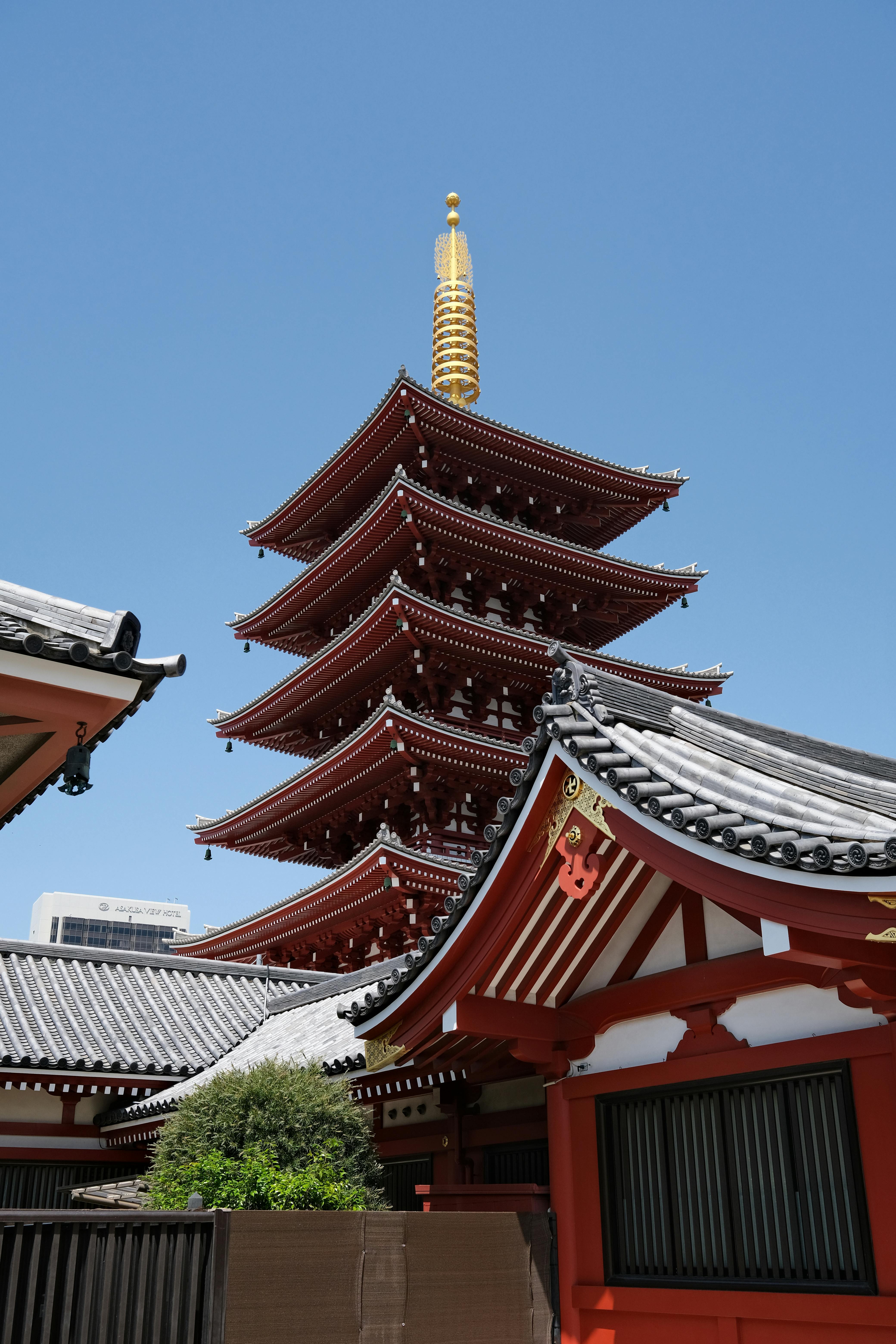 Facade of red Asian temple in green park in sunlight · Free Stock Photo