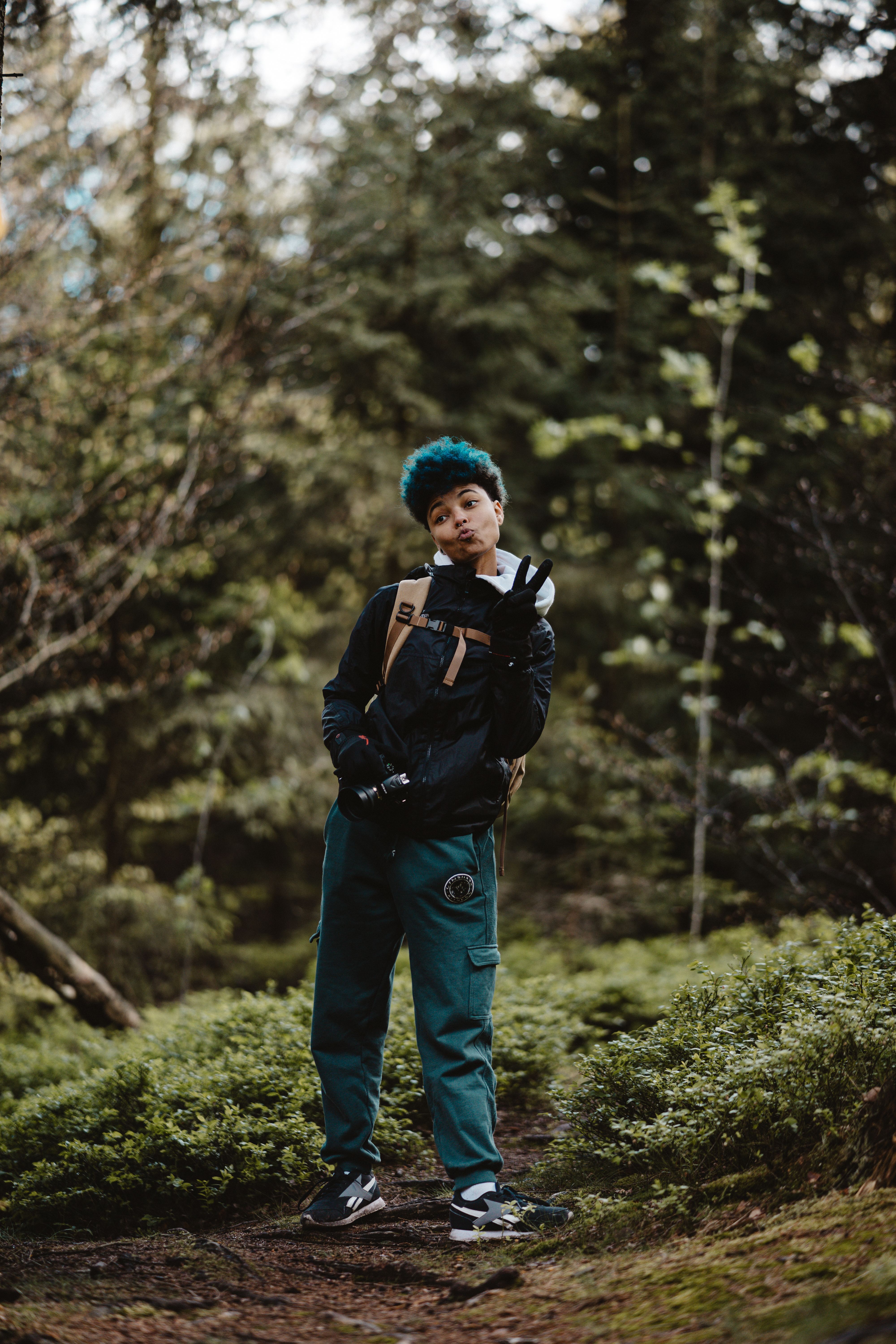 A Boy in Yellow Jacket Near Tree Trunks · Free Stock Photo