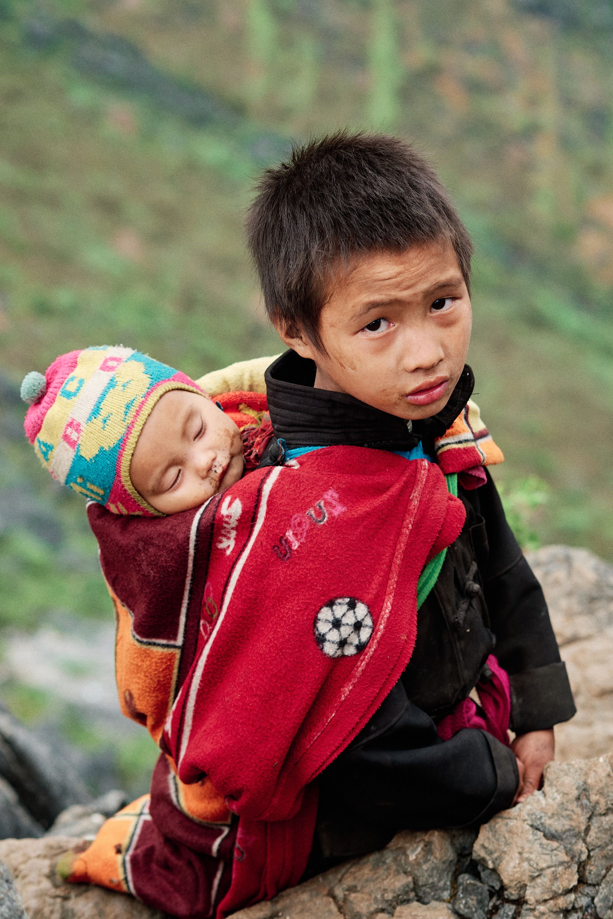 A Boy Carrying His Baby Sibling in a Blanket on His Back · Free Stock Photo
