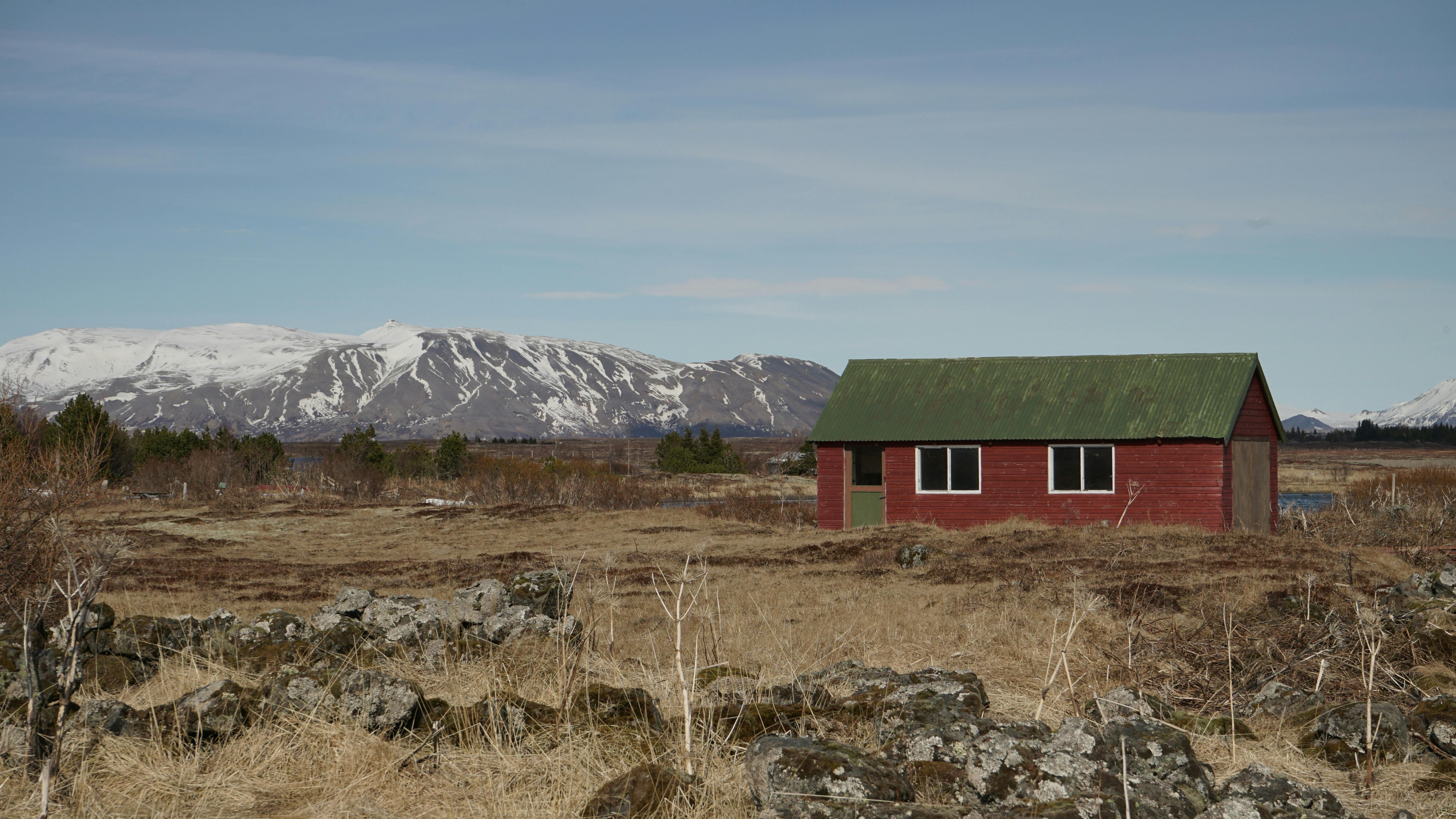 View of a Red Wooden Hut and Distant Snowcapped Mountains · Free Stock ...