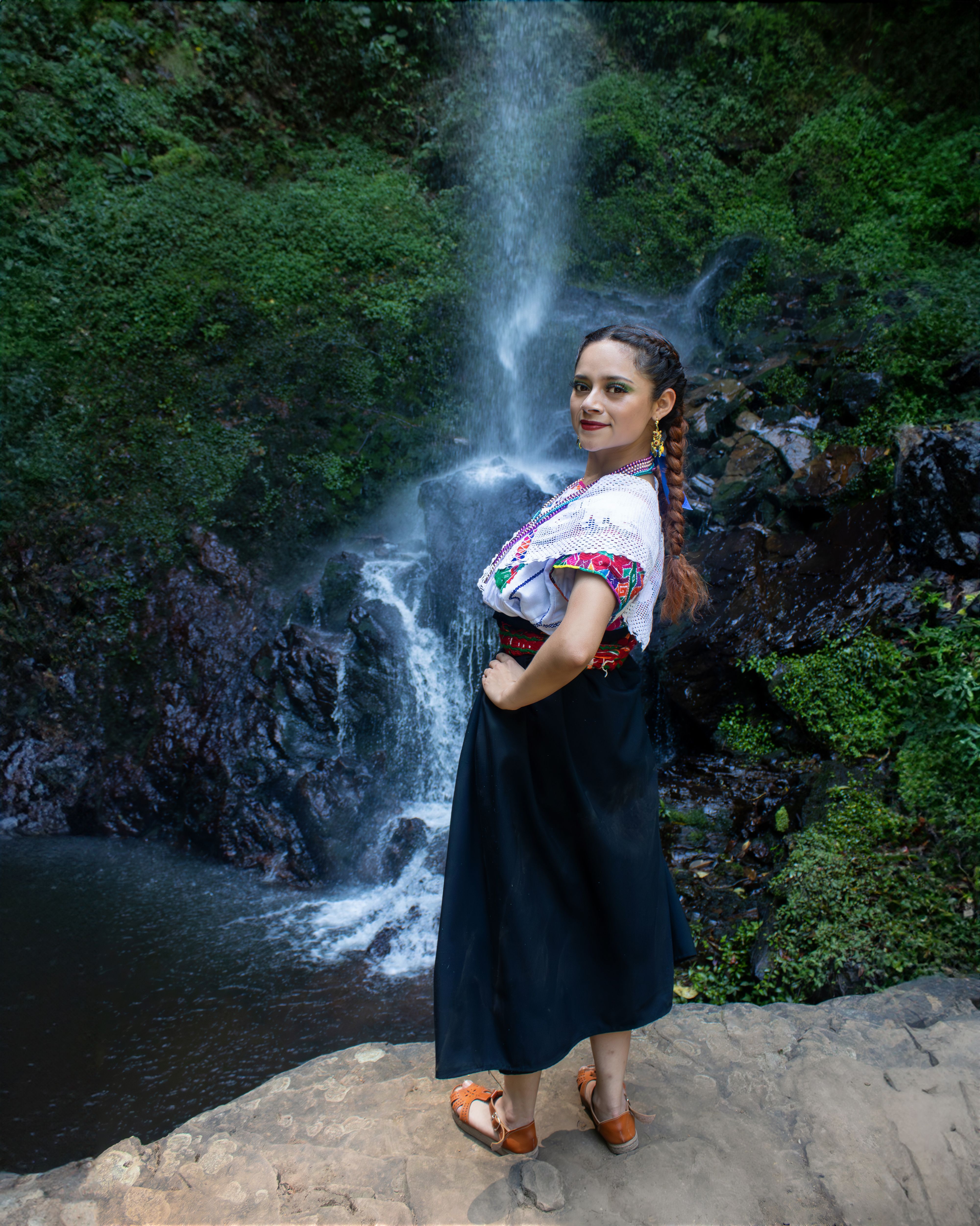A woman in traditional dress standing near a waterfall · Free Stock Photo