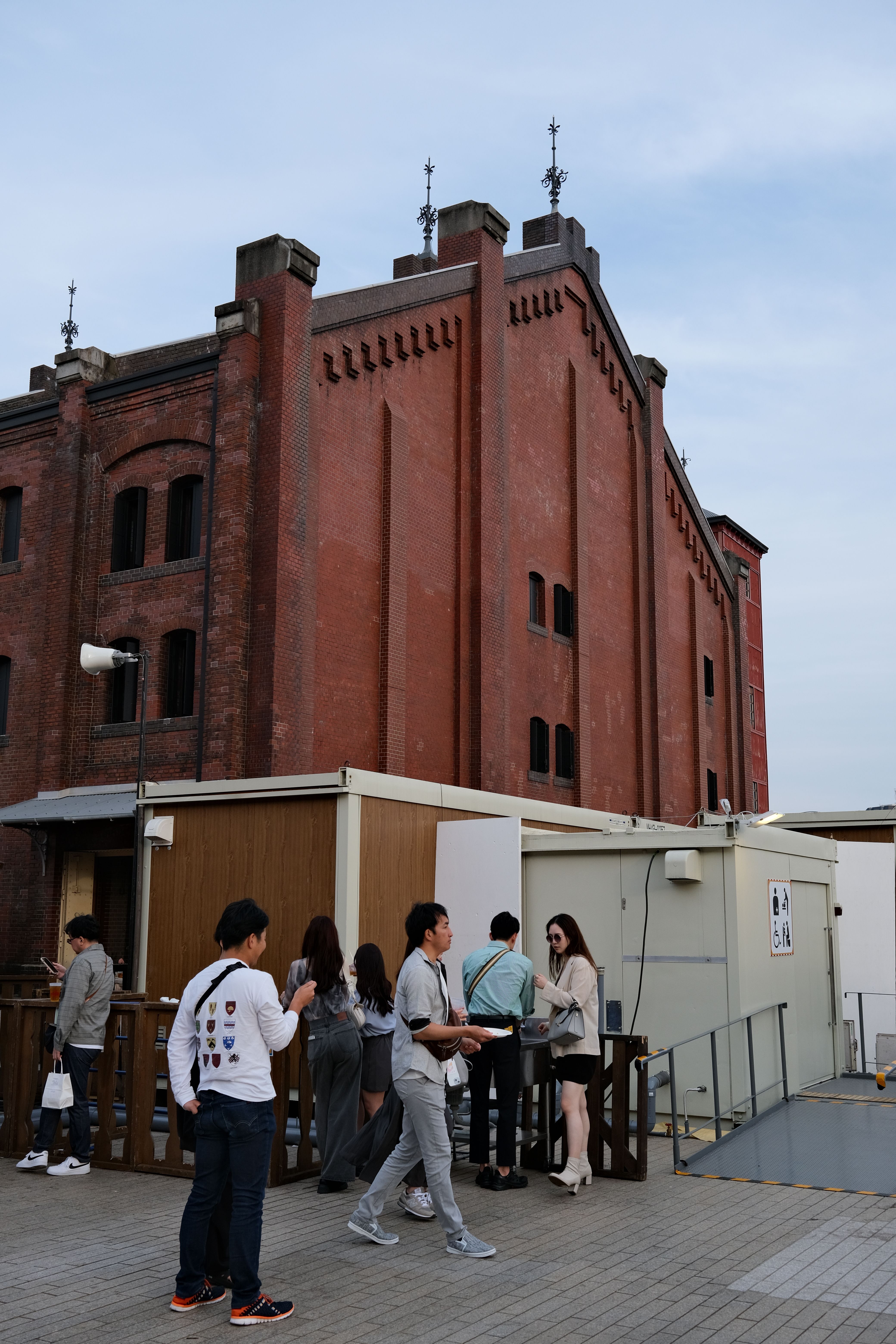 People are walking around a building with a red brick · Free Stock Photo