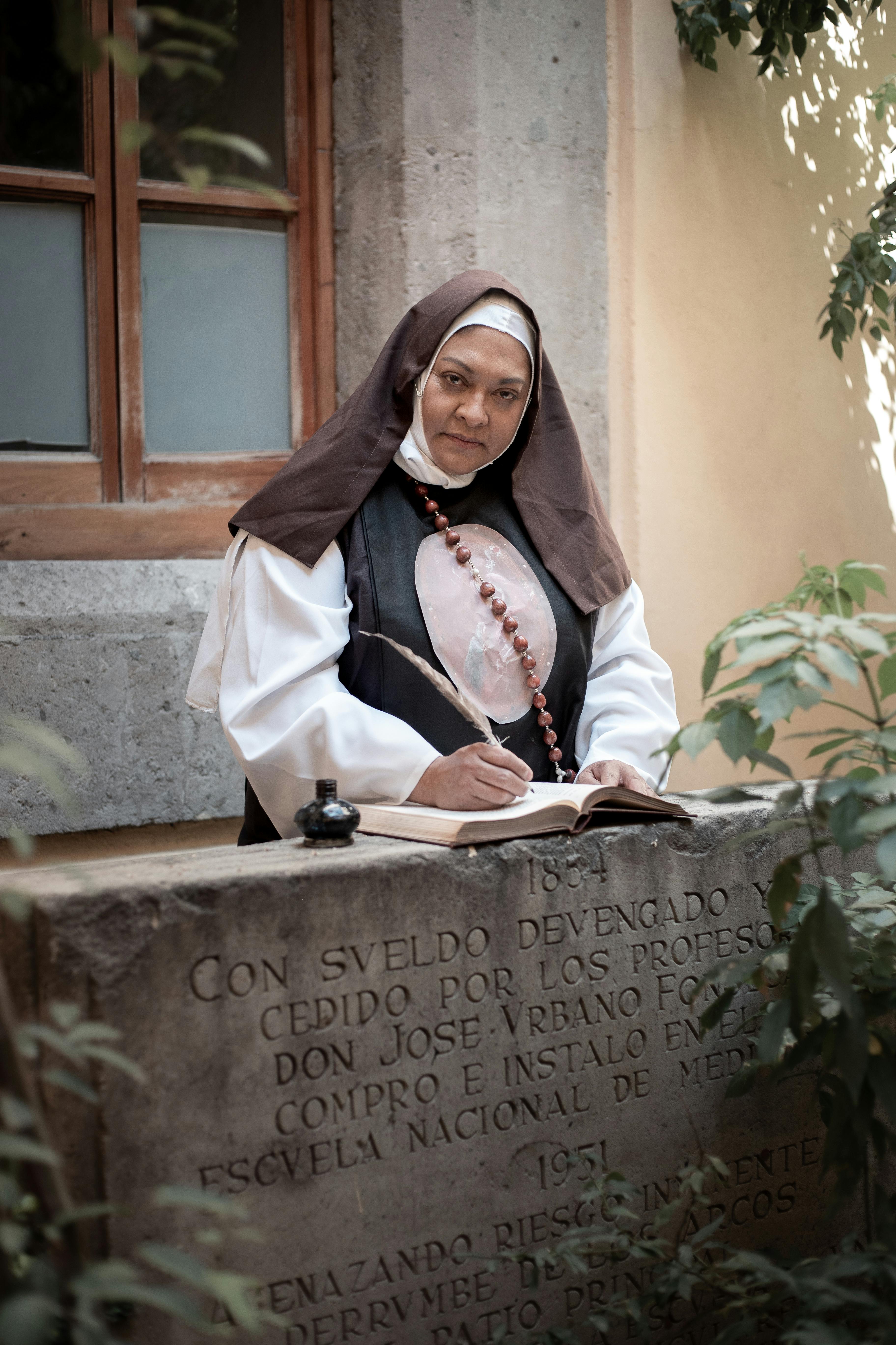 A Nun Writing in a Notebook with a Quill · Free Stock Photo