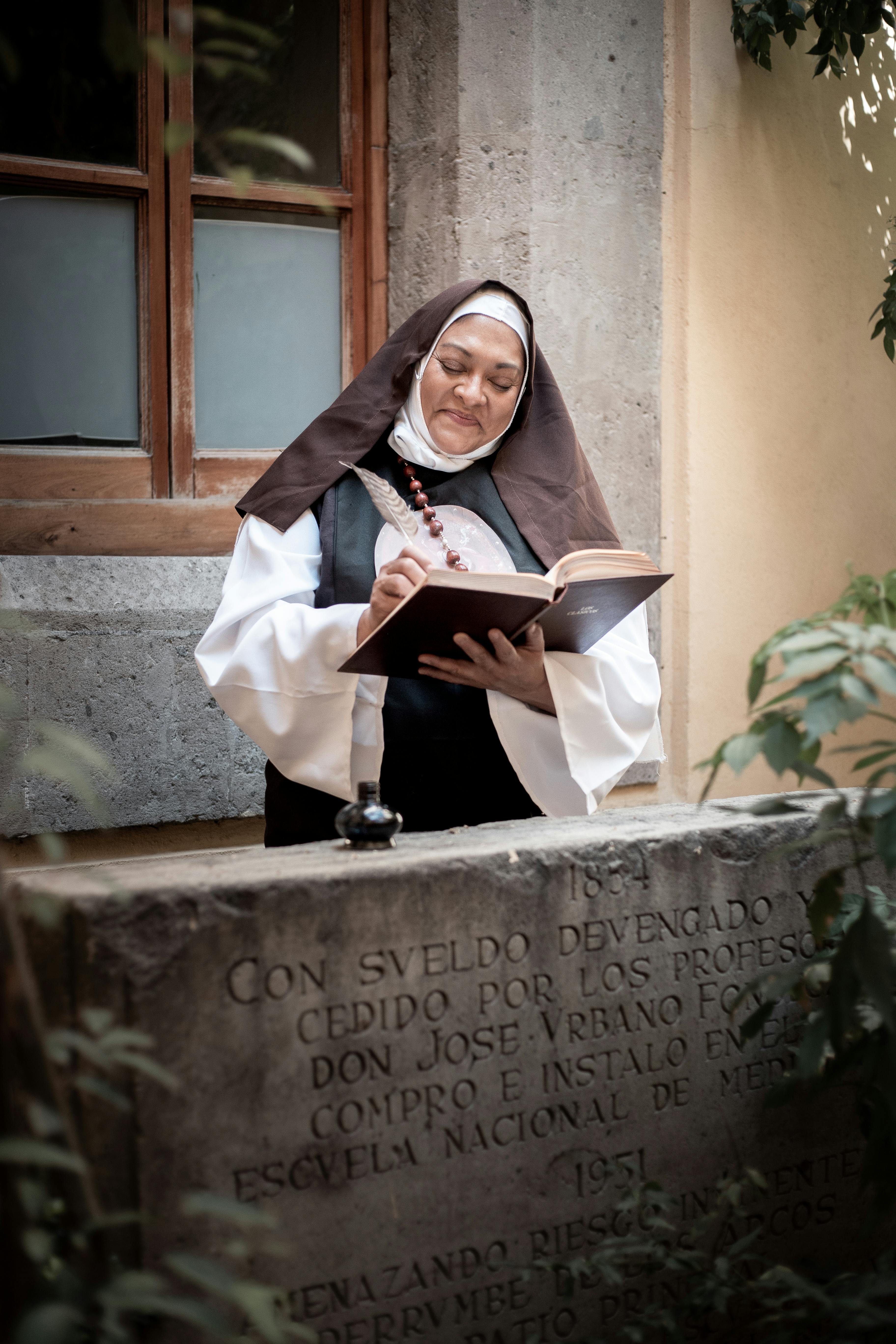 A Nun Writing in a Notebook with a Quill · Free Stock Photo