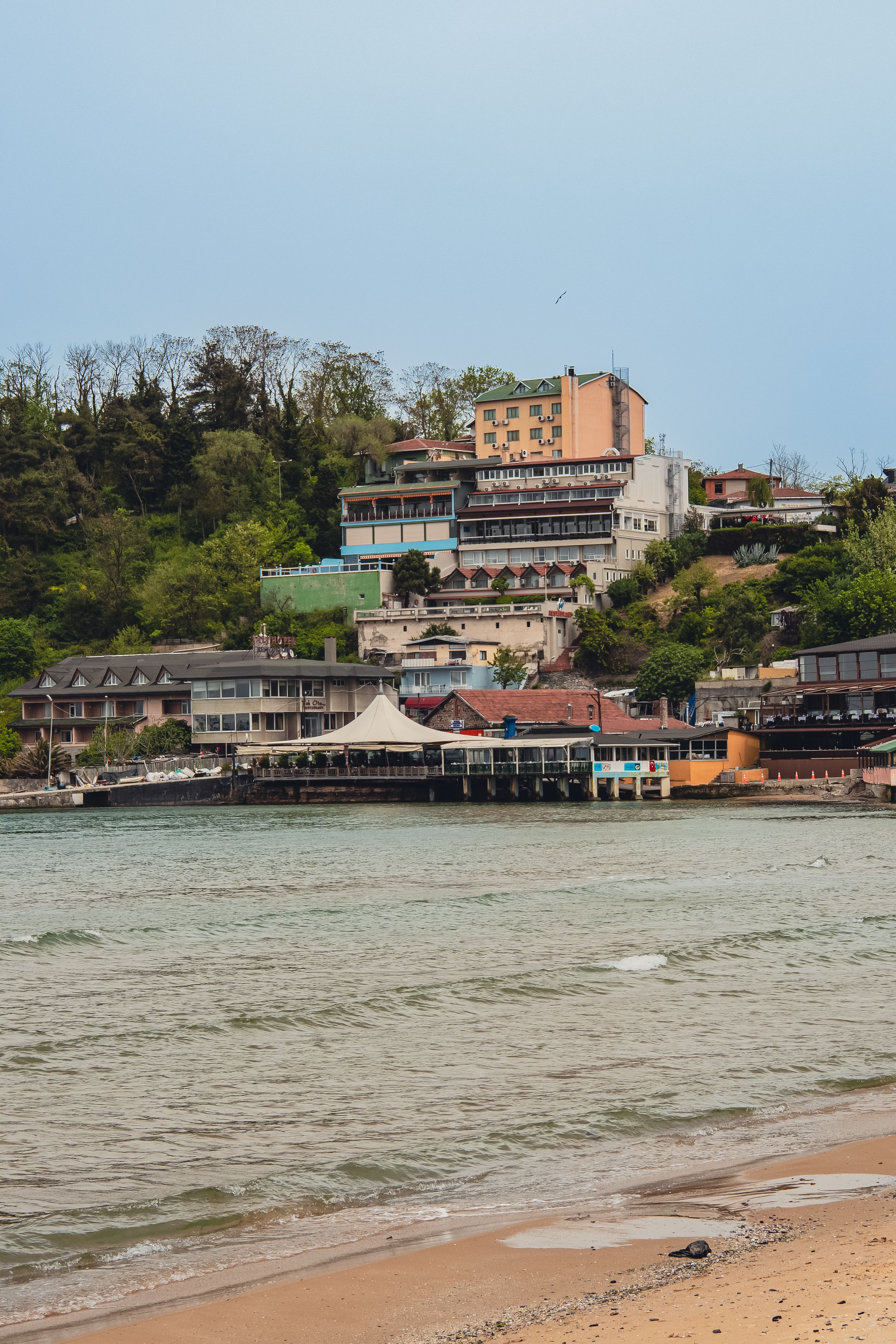 A beach with a building on it and a hill · Free Stock Photo
