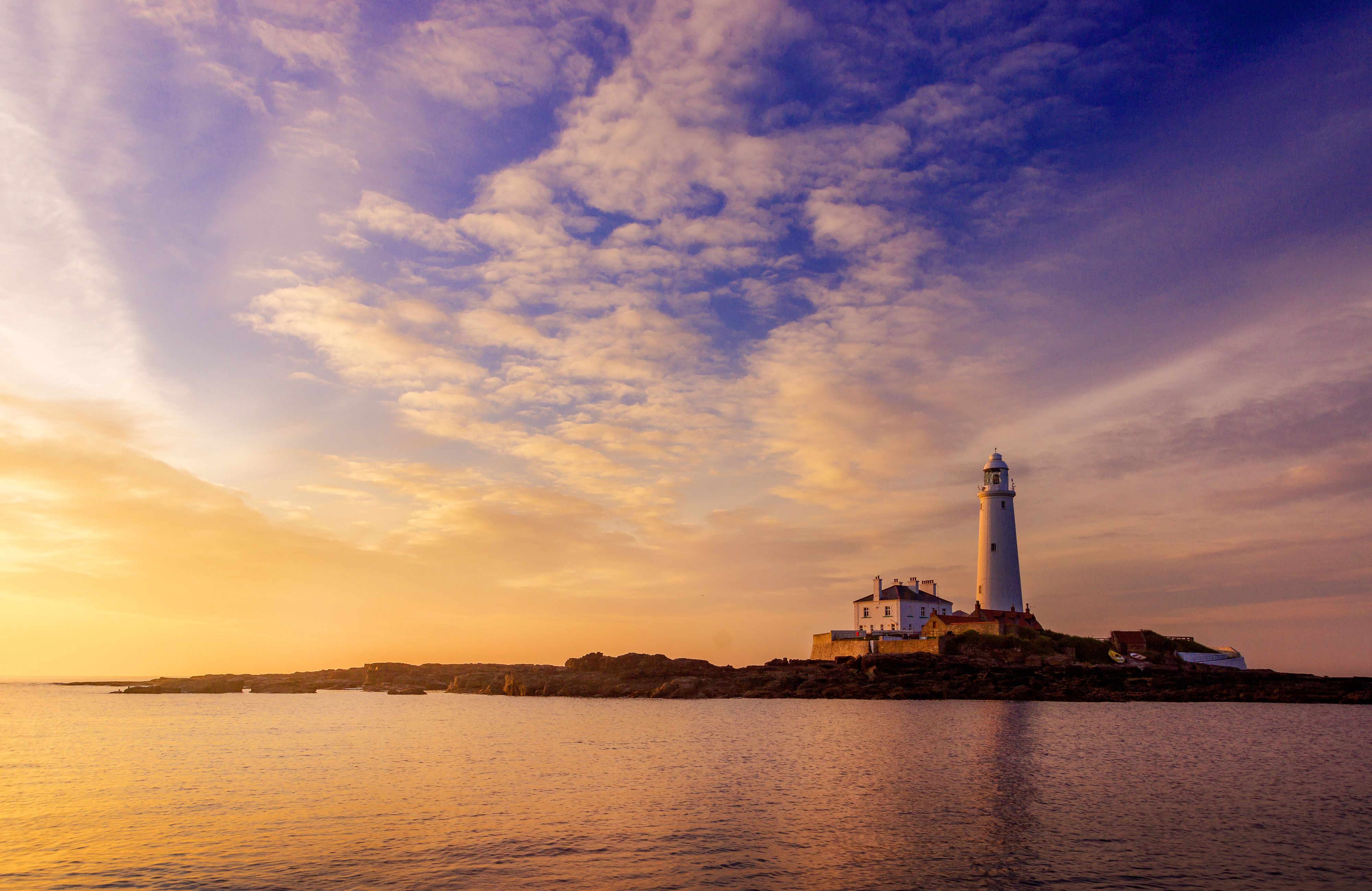 A lighthouse on an island at sunset · Free Stock Photo